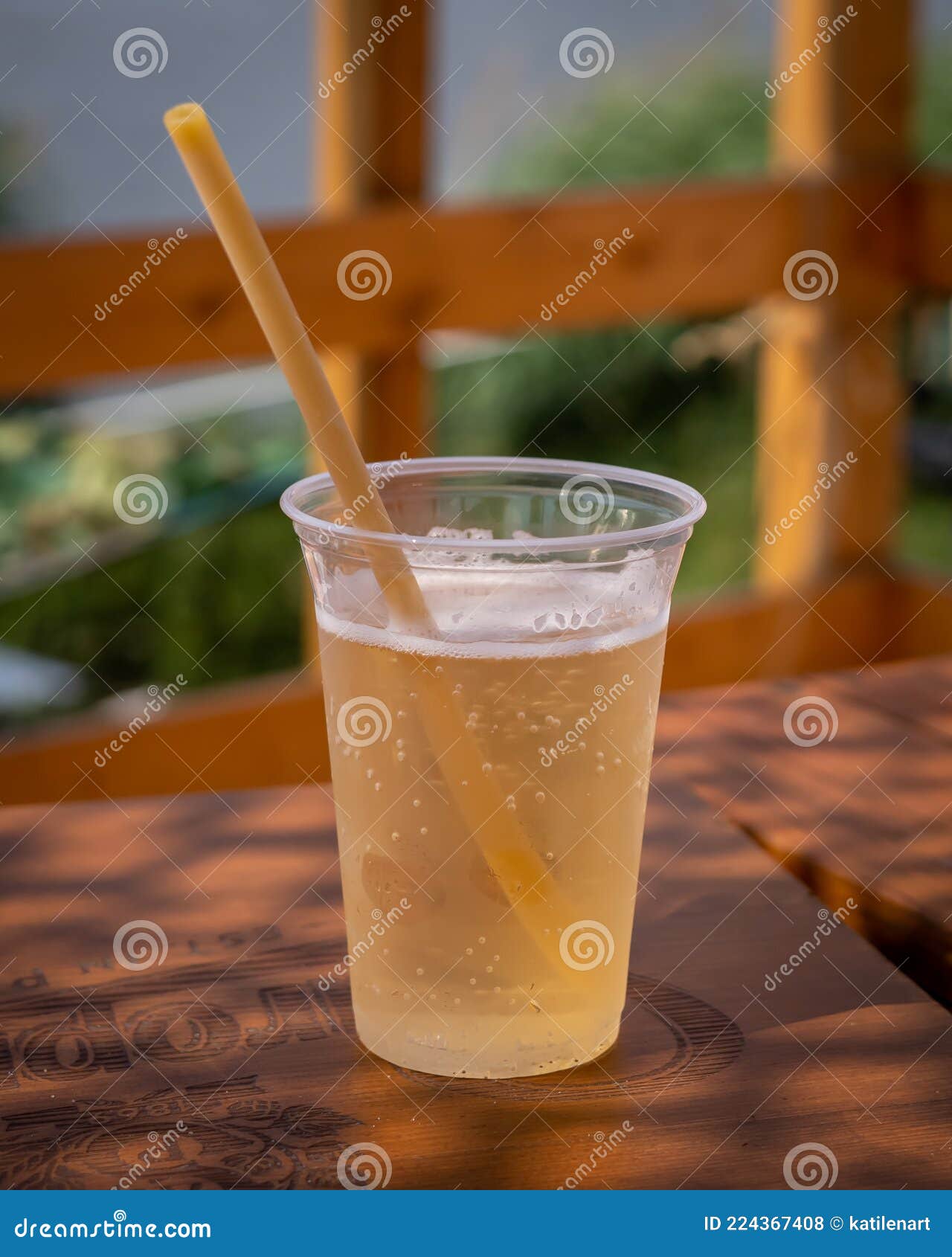 A Plastic Cup of Apple Cider with a Biodegradable Straw, on a Wooden ...