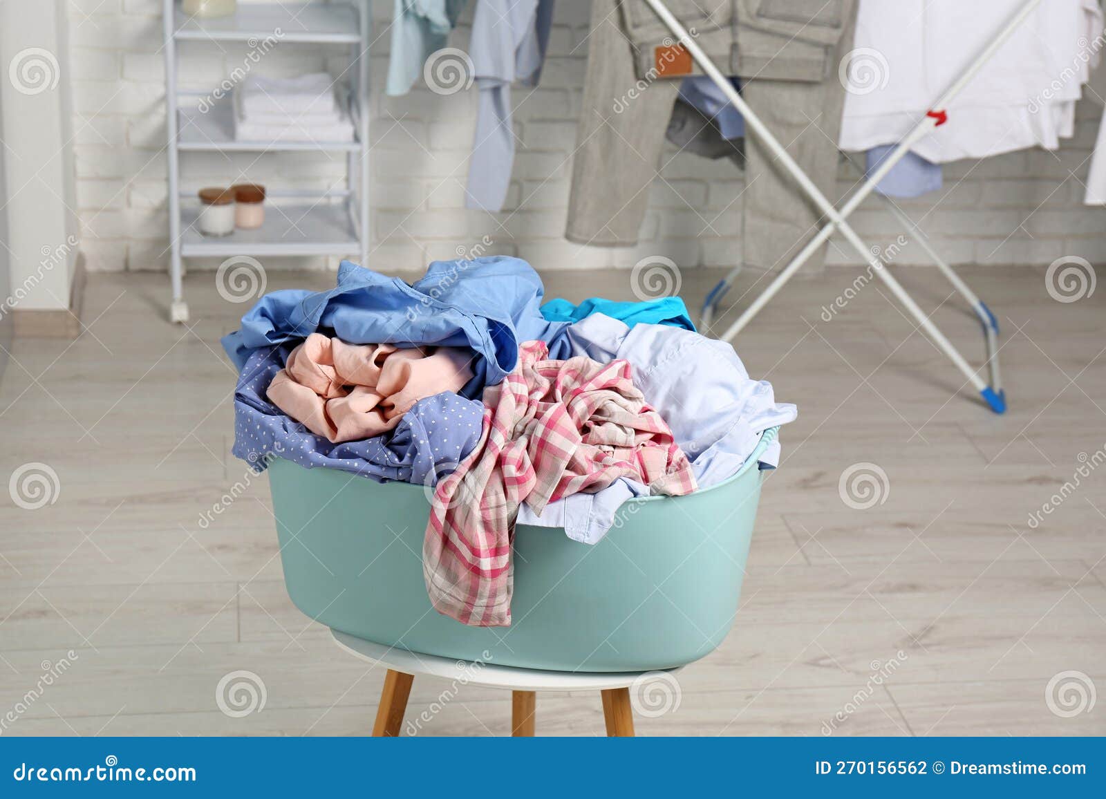 Plastic Laundry Basket Overfilled with Clothes on White Stool Indoors ...