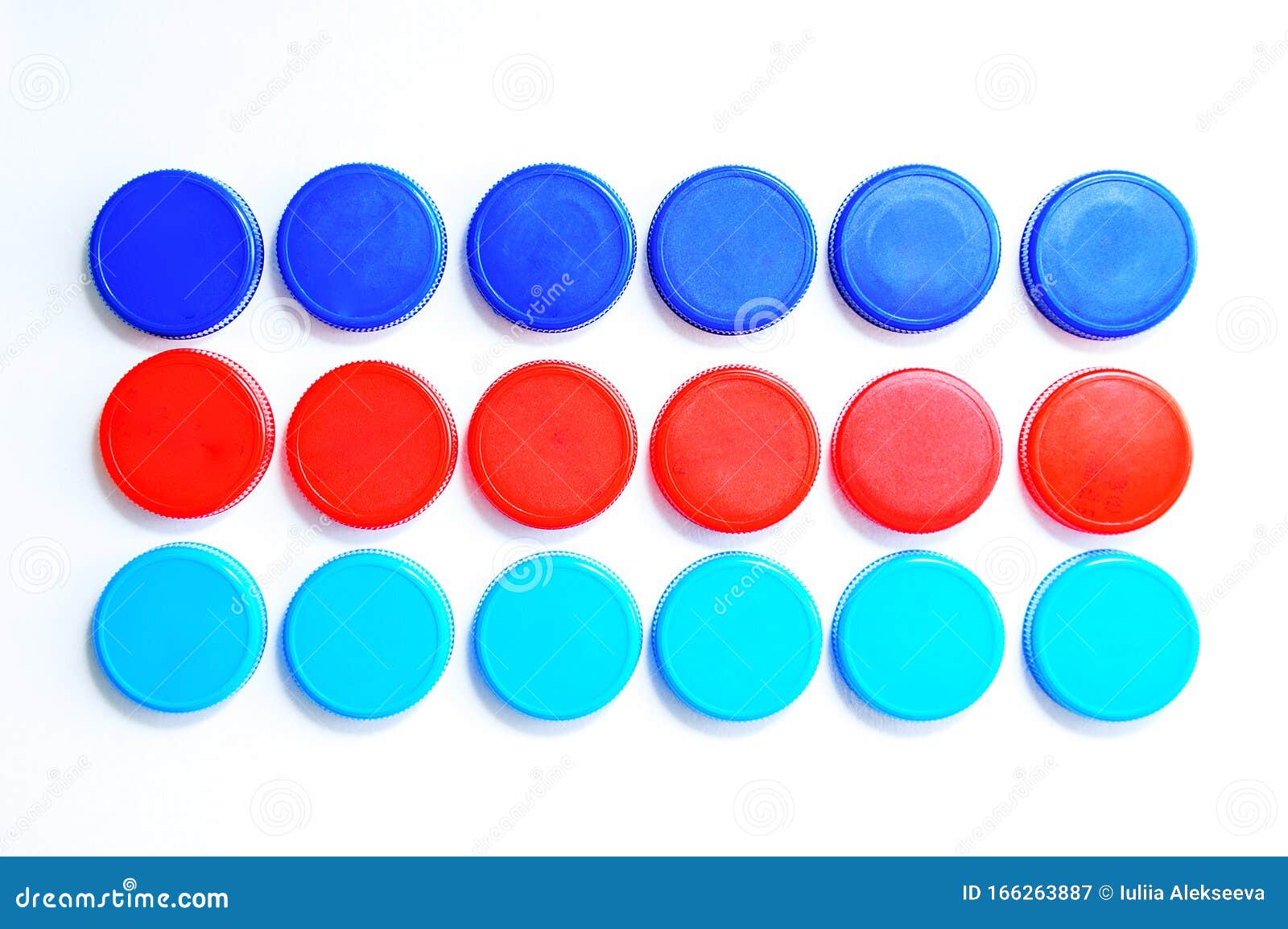 Plastic Multi-colored Bottle Caps are Arranged in Three Rows on a White ...