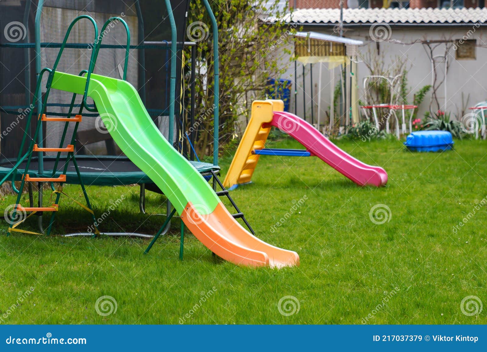 Plastic Multi-colored Slides on the Playground. Green Grass on the Lawn ...