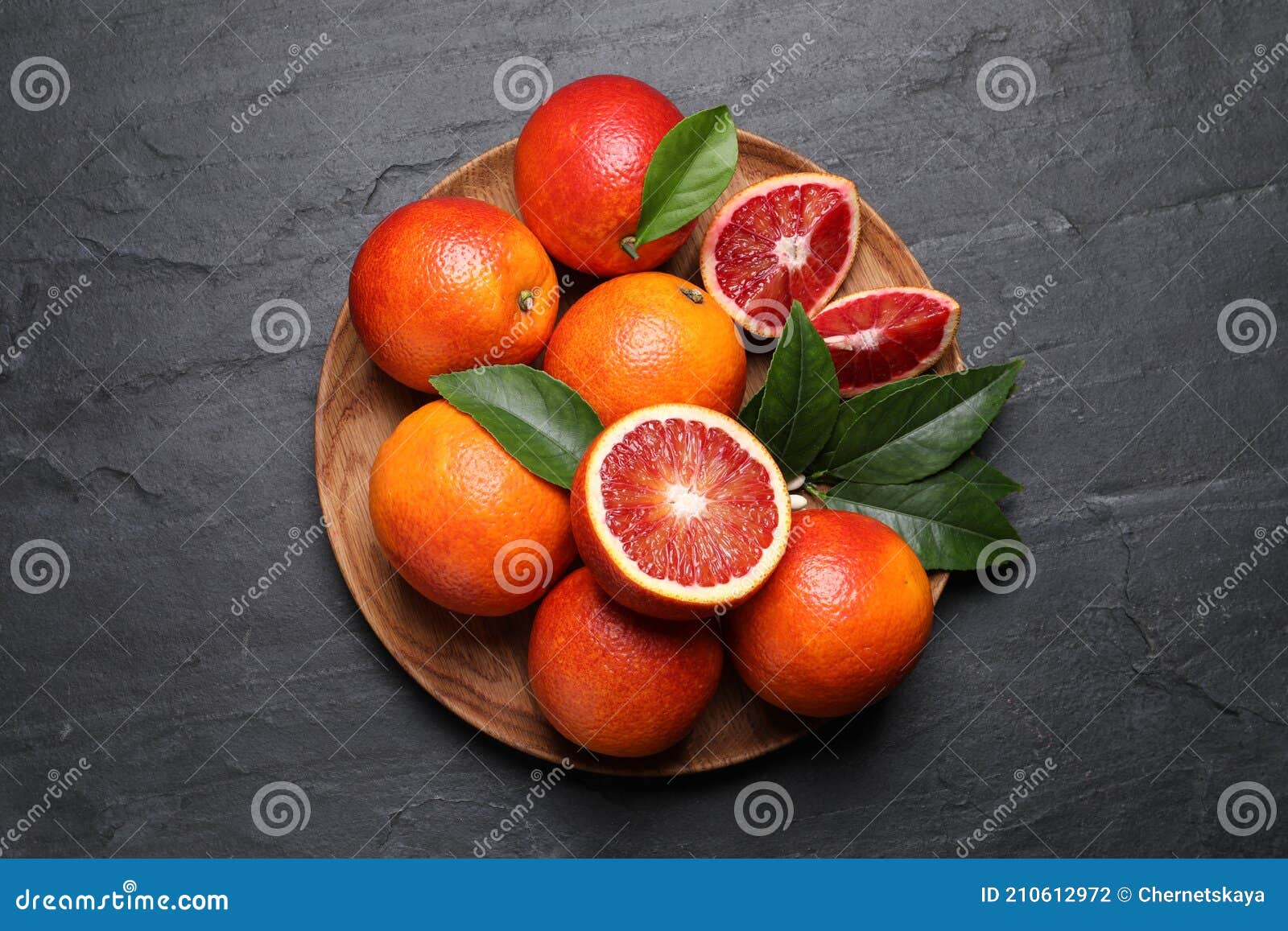 Plate of Ripe Red Oranges and Green Leaves on Dark Table, Top View ...