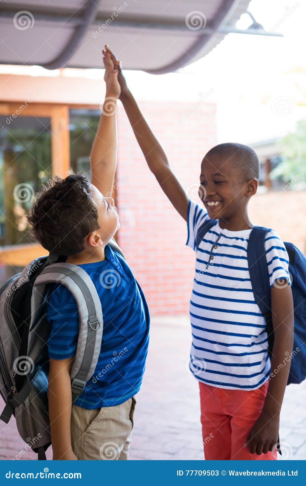 Playful Classmates Giving High-five at Corridor Stock Image - Image of ...