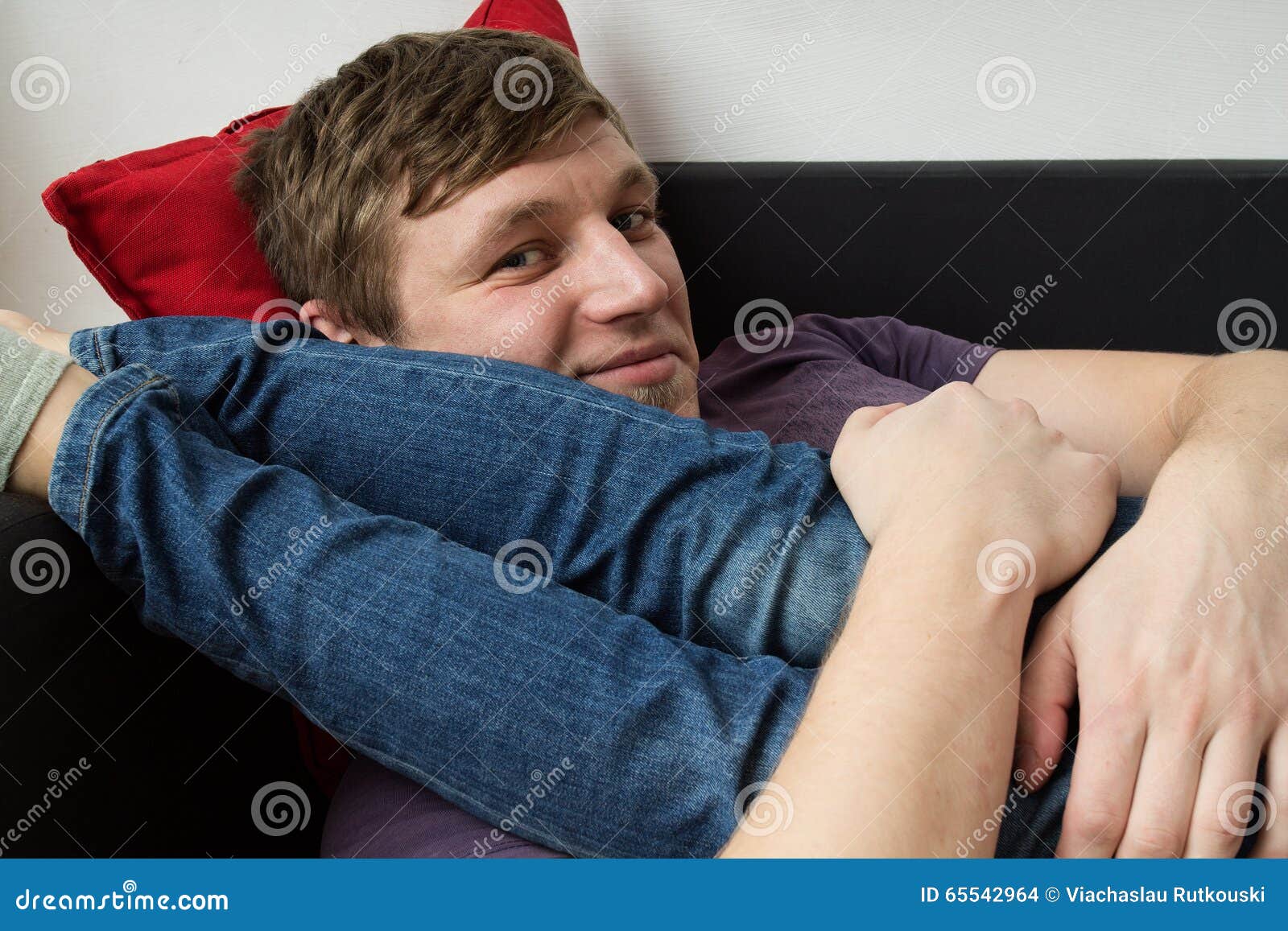 Pleased Man Lying on the Couch, Hugging a Female Legs, Smiling a Stock ...