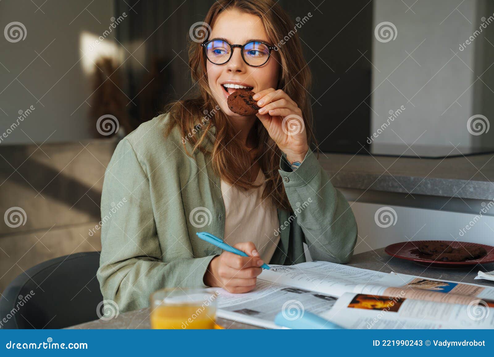 Pleased Student Woman Eating Cookie while Doing Homework at Home Stock ...