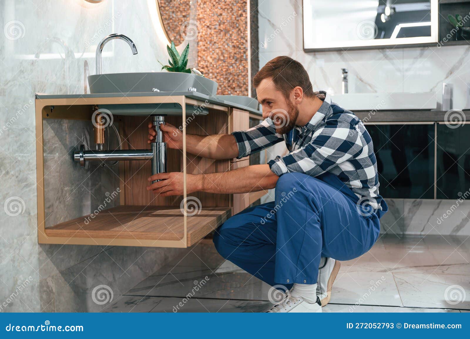 Plumber in Blue Uniform is at Work in the Bathroom Stock Image - Image ...