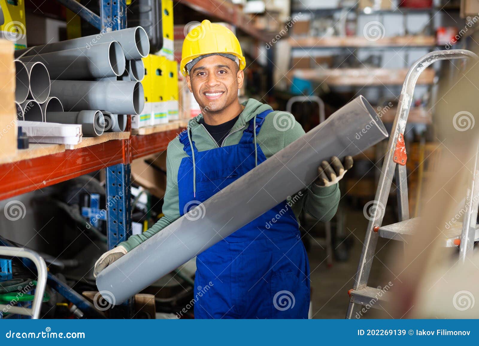 Plumber in Protective Helmet and Overalls Selects Plastic Pipes in ...