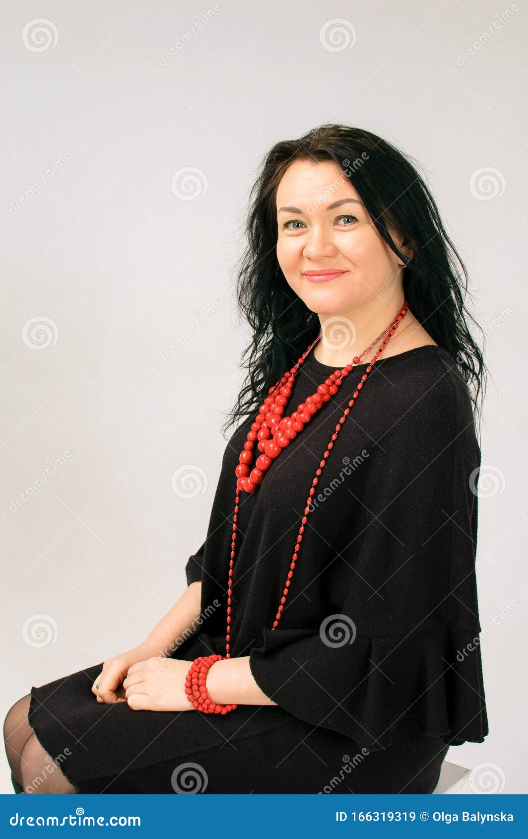 Plus Size Model in Black Dress and Red Ethnic Necklace Sitting on the ...
