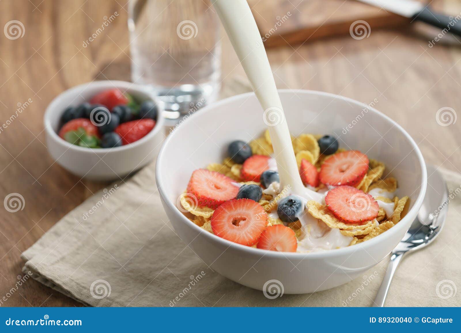 Poring Milk into Corn Flakes with Berries in Bowl on Table Stock Photo ...