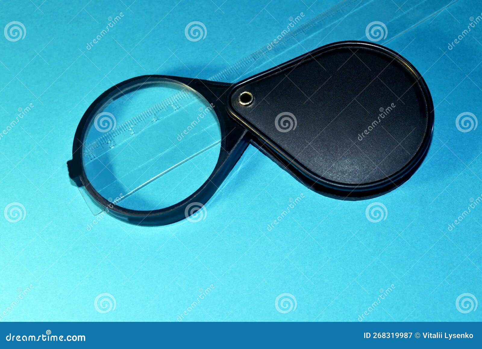 A Portable Folding Magnifier Lies on a Centimeter Ruler on a Blue ...