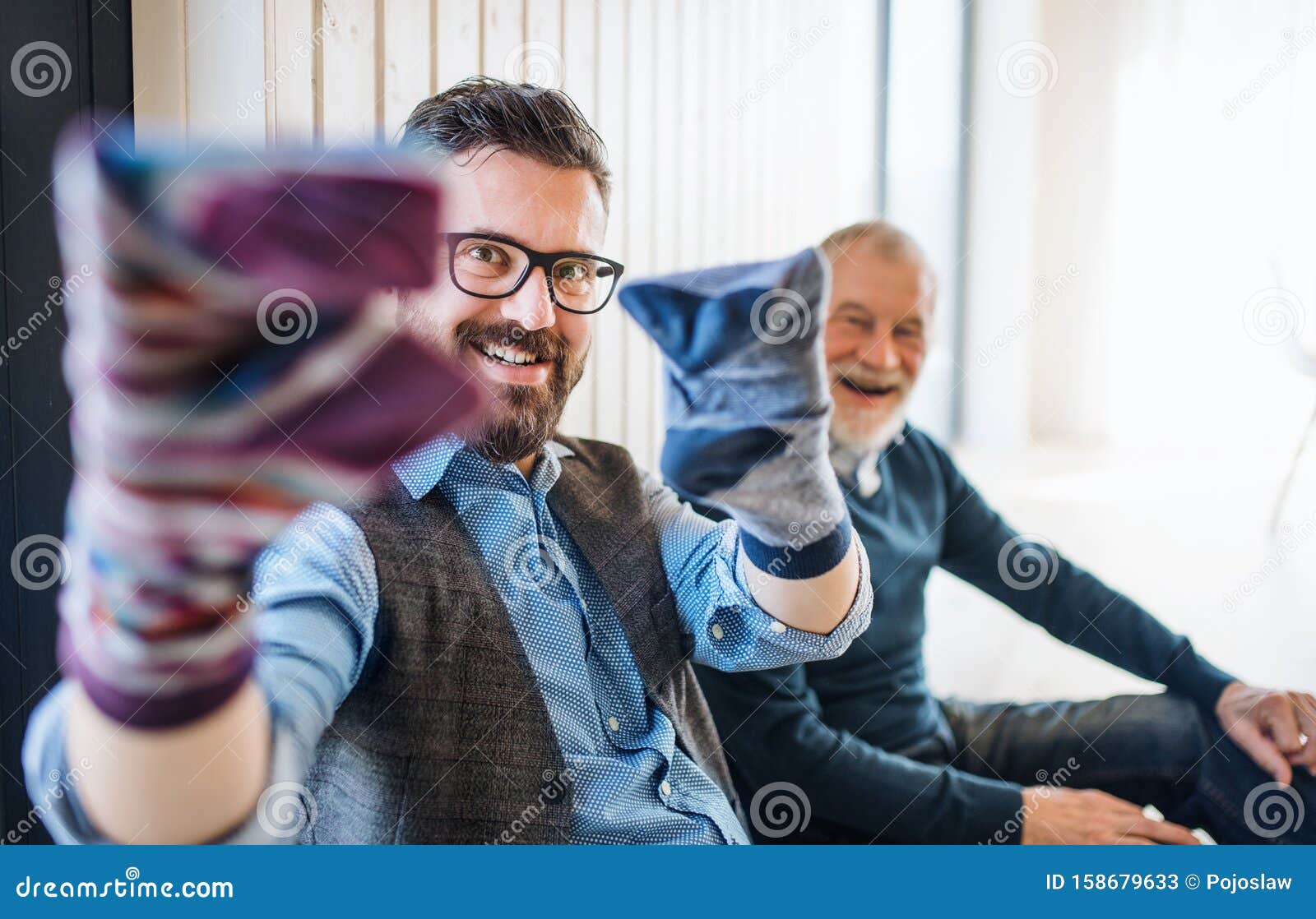 Portrait Of Adult Hipster Son And Senior Father Sitting On Floor