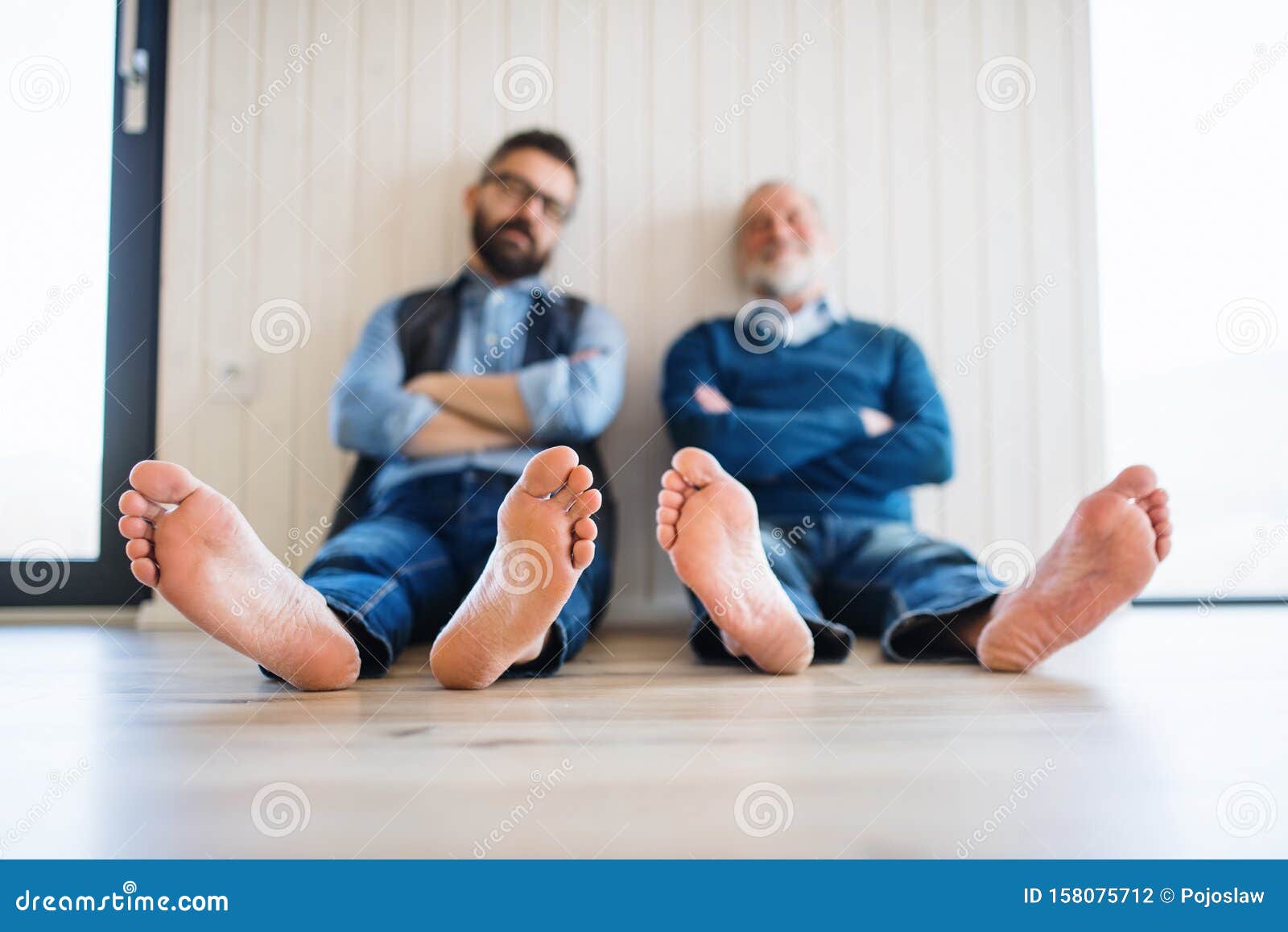A Portrait Of Adult Hipster Son And Senior Father Sitting On Floor