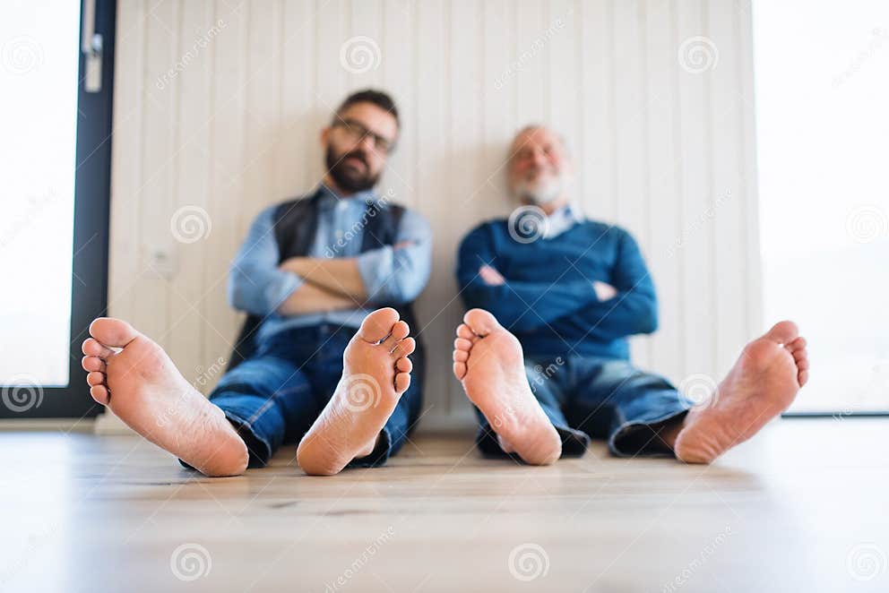 A Portrait Of Adult Hipster Son And Senior Father Sitting On Floor