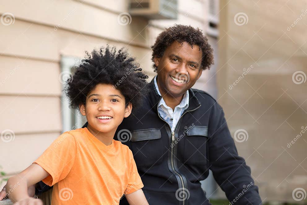 African American Father Hugging His Son And Smiling Stock Image