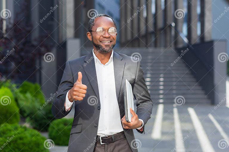 Portrait Of African American Male Teacher Looking At Camera Holding
