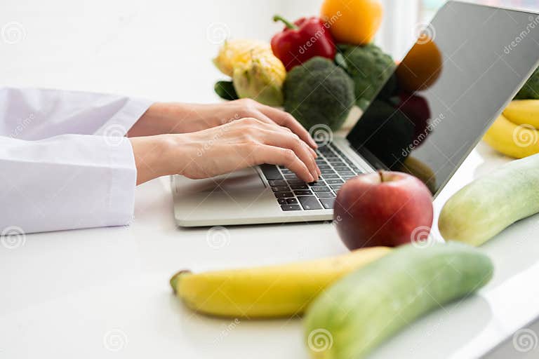 Portrait Of Asian Smiling Female Nutritionist Typing On Laptop Computer