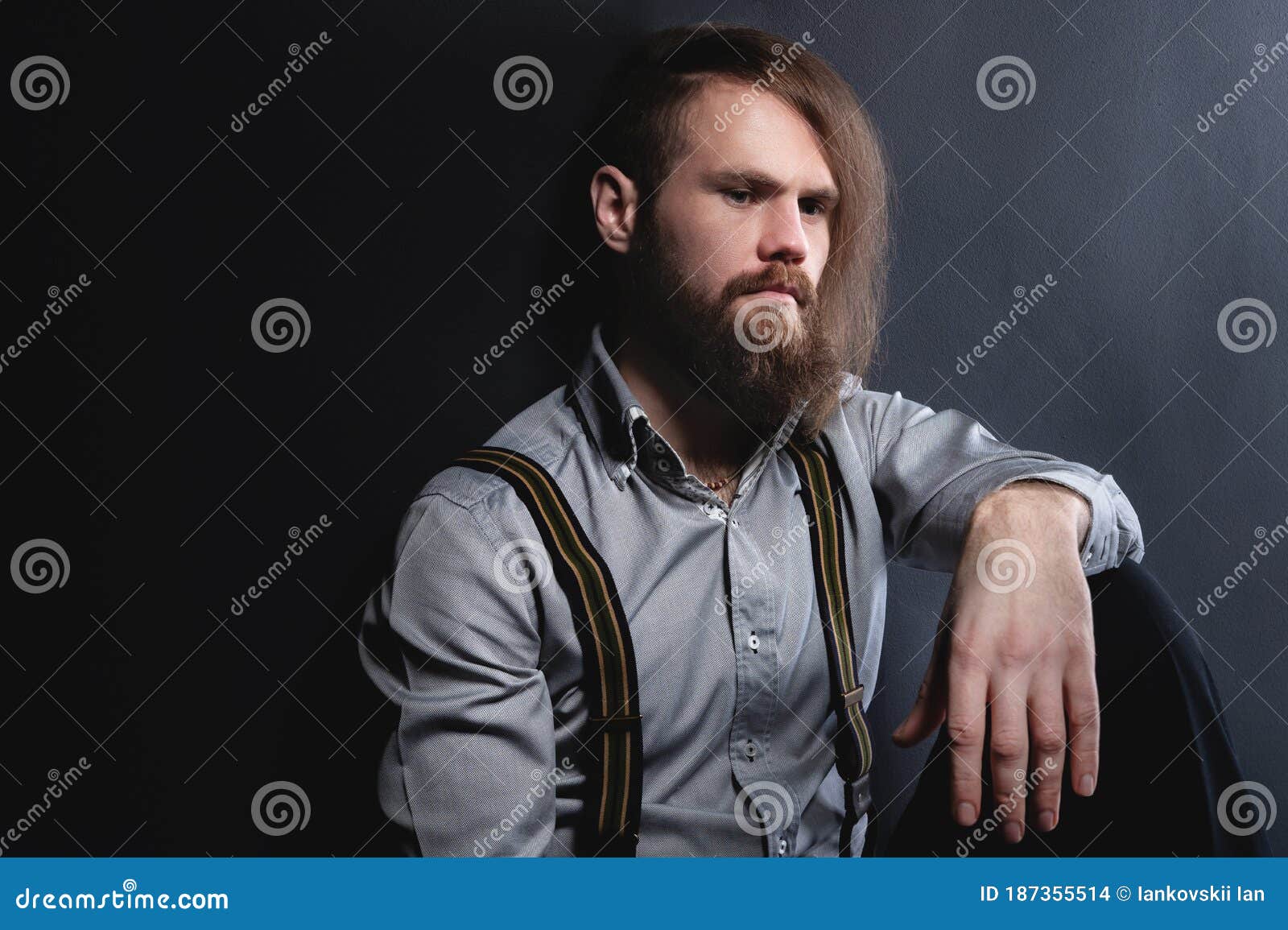 A Portrait of an Attractive Brooding Bearded Man Sitting Against a Wall ...