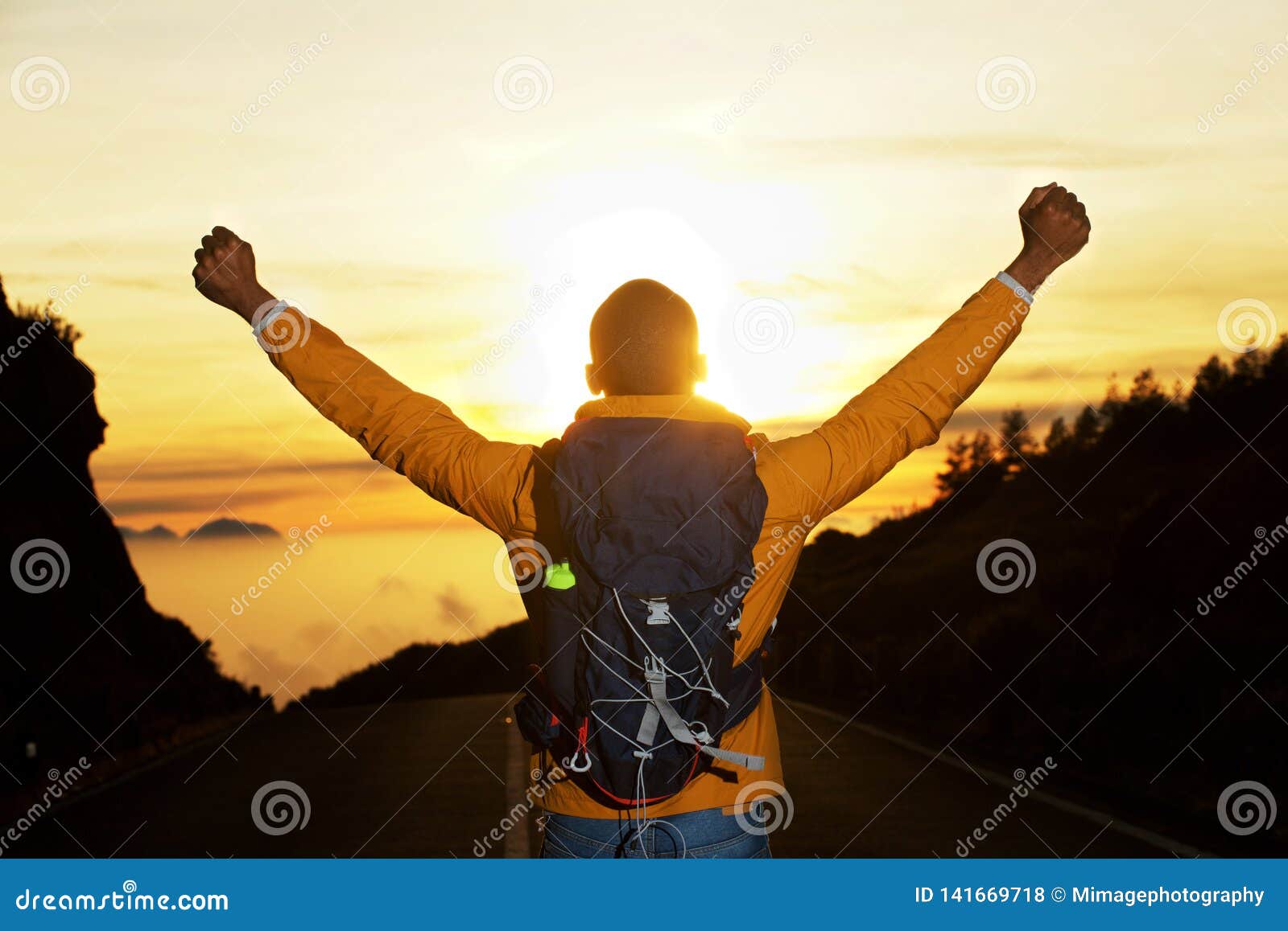 Back of Man with Backpack with Arms Raised during Sunset Stock Photo ...