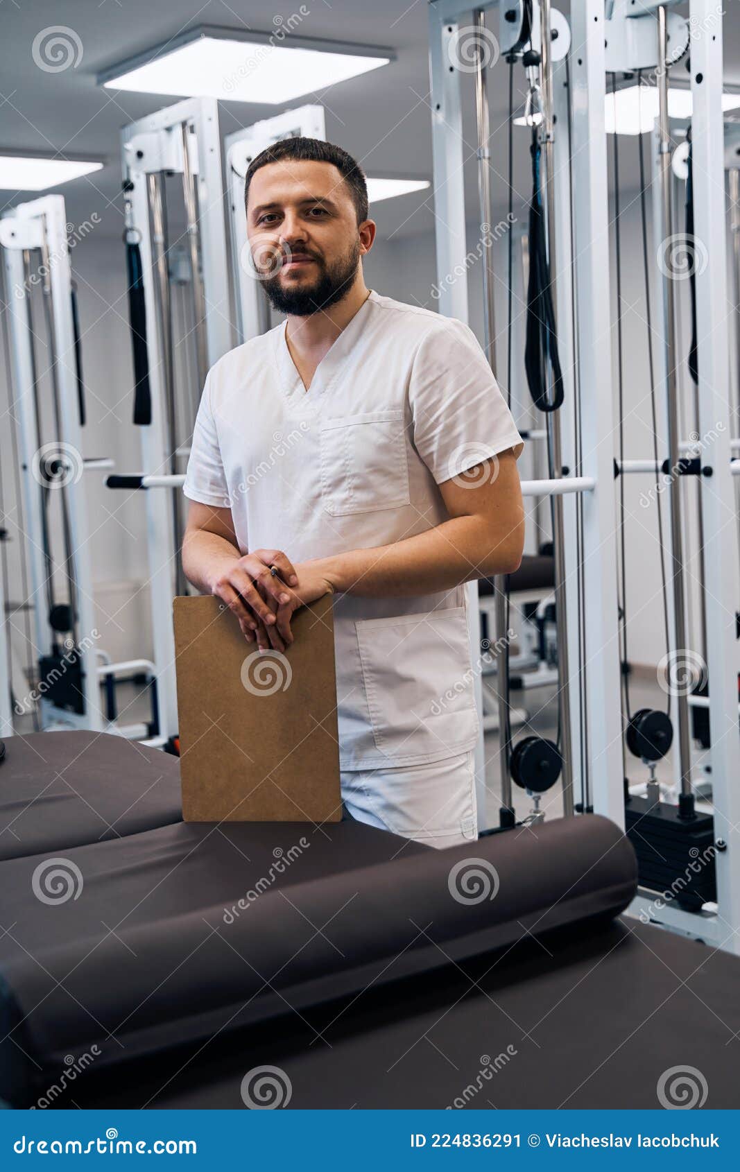 Portrait Of Bearded Caucasian Doctor With Clipboard In Hands Serious