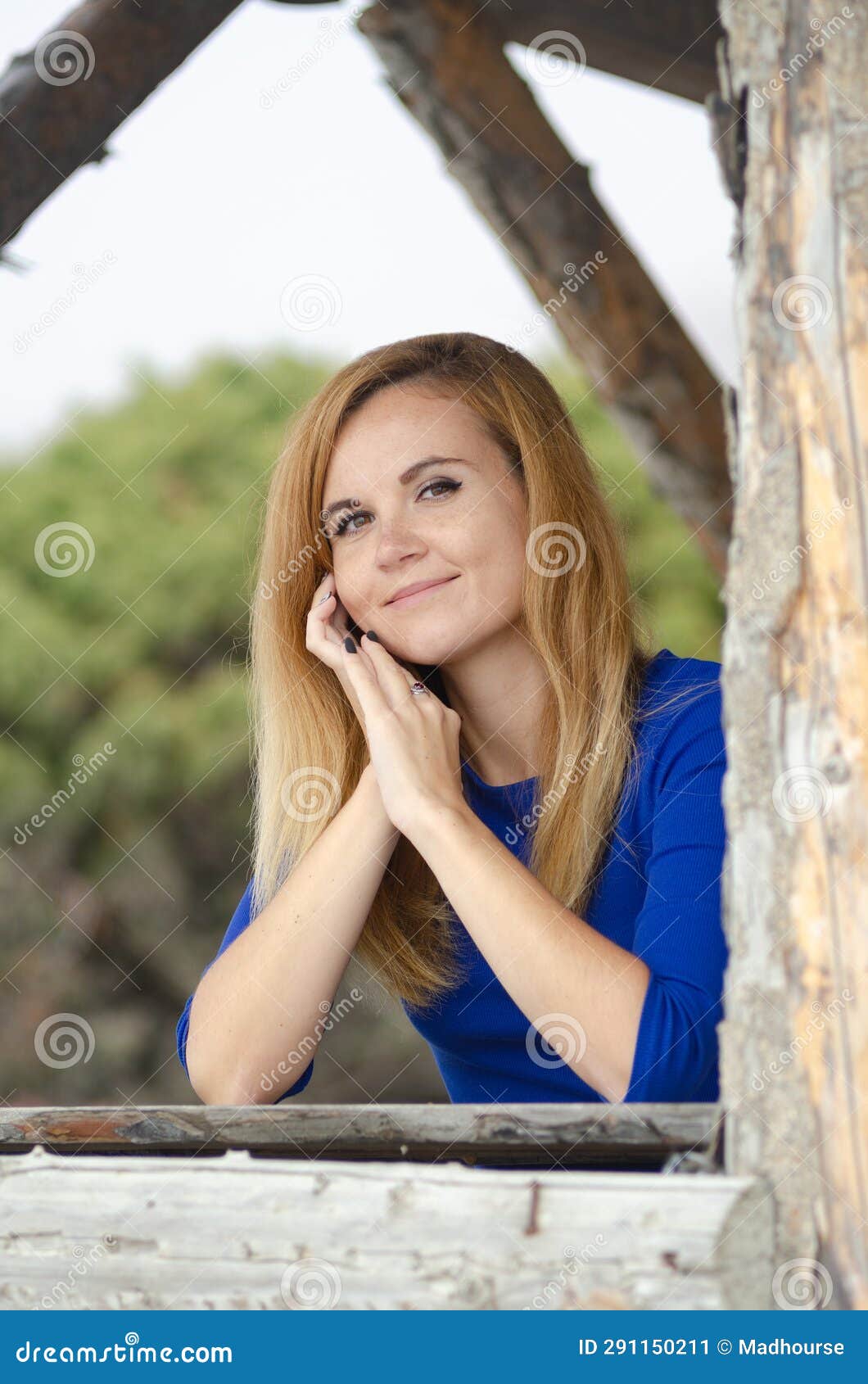 Portrait Of A Beautiful Blonde Woman In A Blue Dress Against The