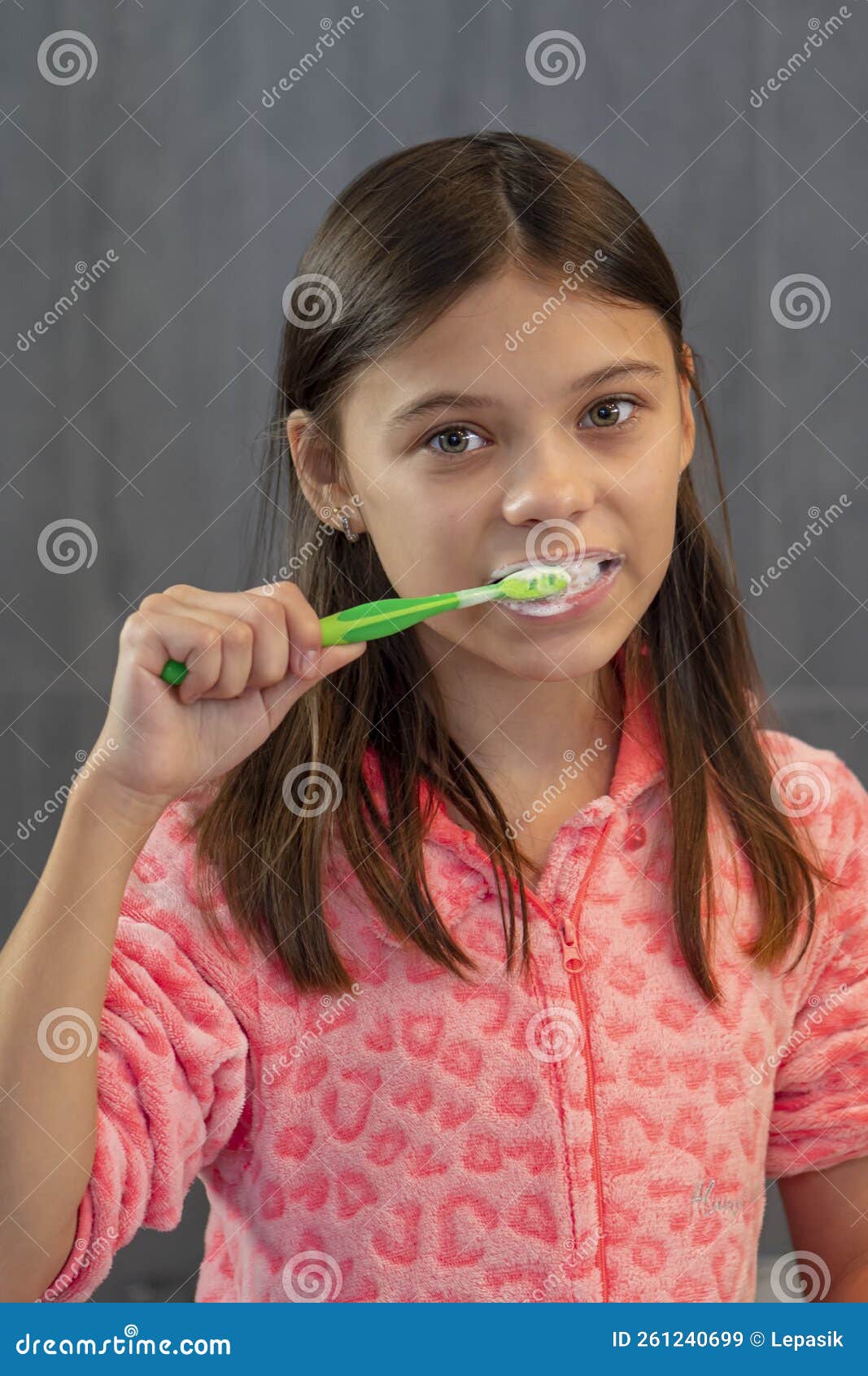 Portrait Of A Beautiful Girl Brushing Her Teeth In Pink Pajamas On A