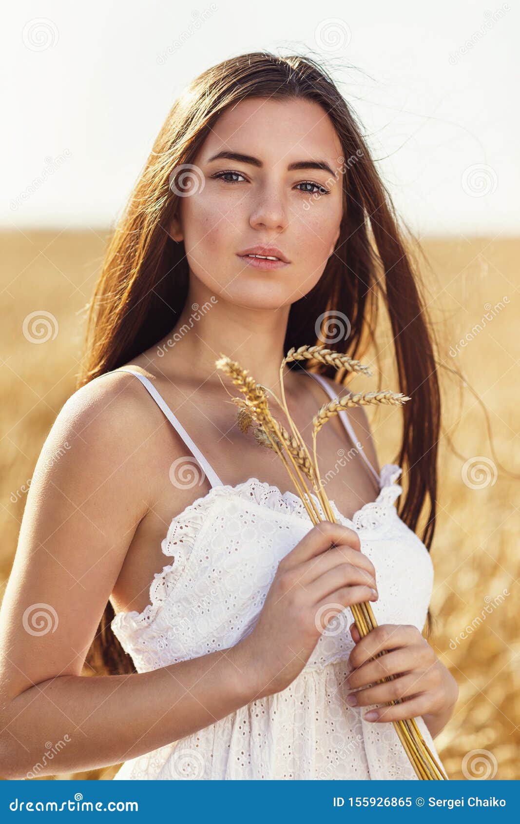 Portrait Of A Beautiful Girl In The Sun Holding Ripe Spikelets Of Wheat