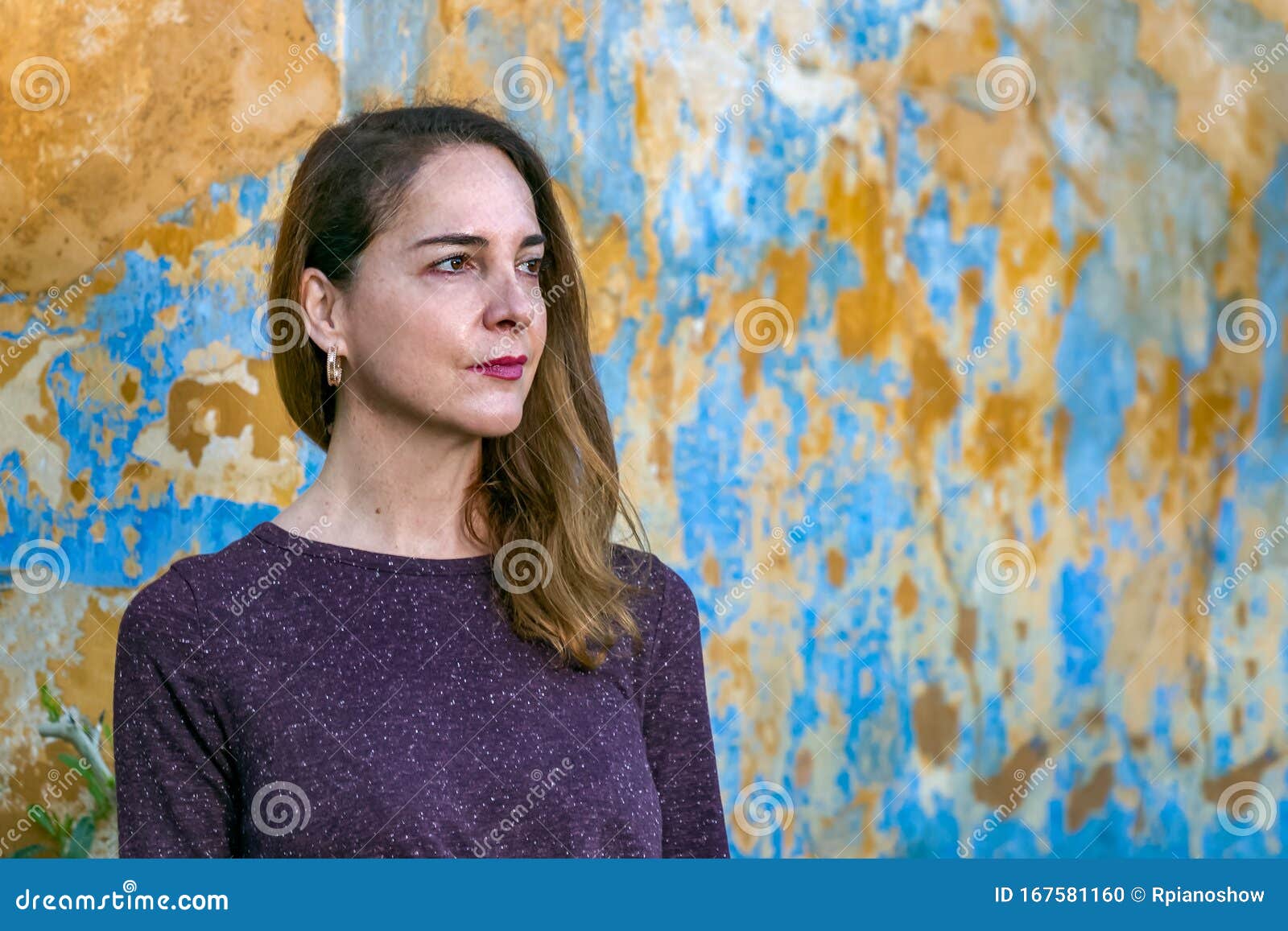 Portrait Of A Beautiful Mature Woman Looking Away Over A An Old Wall
