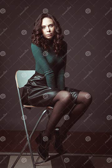 Portrait Of Beautiful Woman With Makeup On A Chair In Green Sweater
