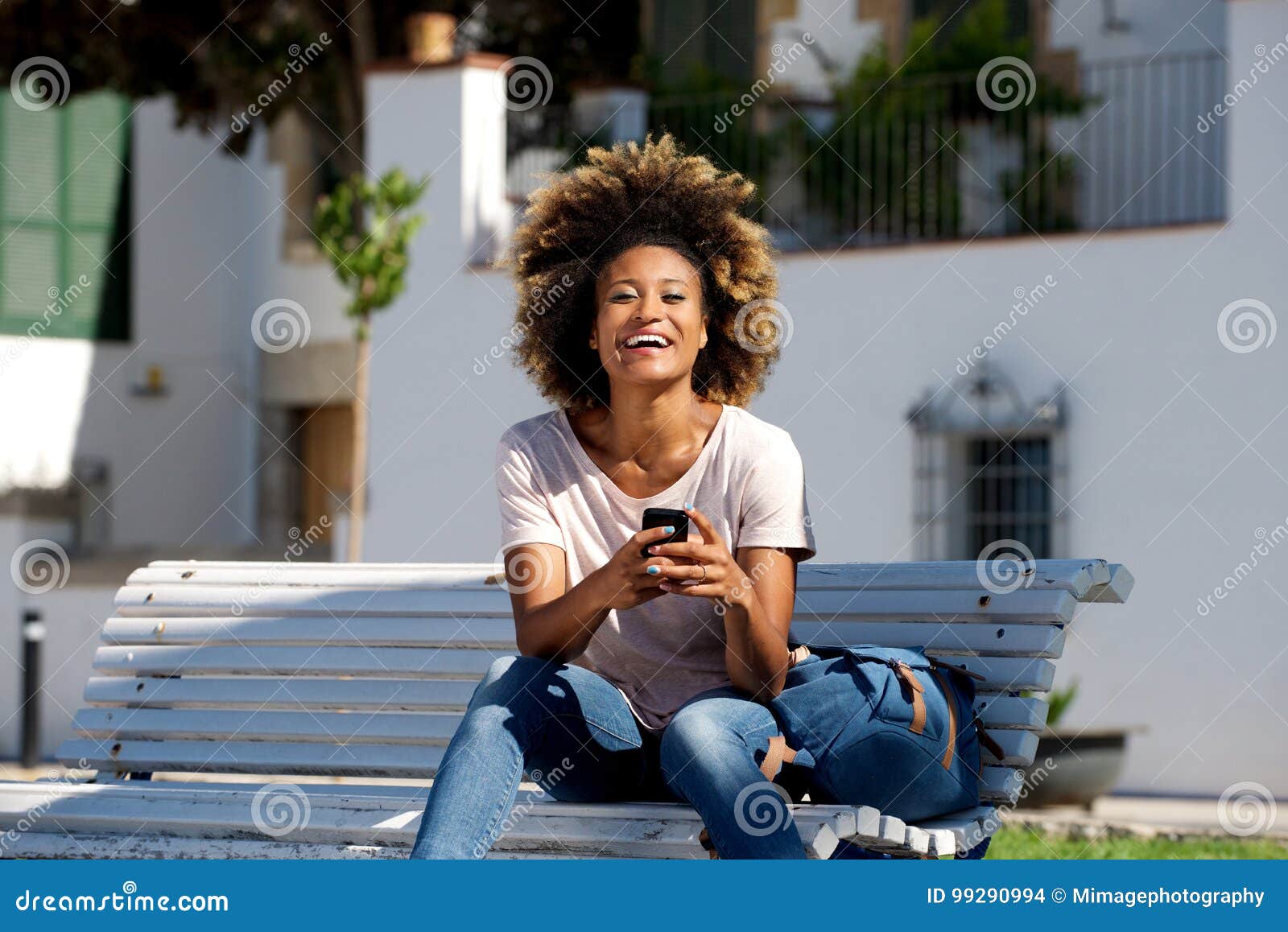 Beautiful Young African Woman Sitting Outdoors on Bench with Mobile ... Beautiful Young African Woman Sitting Outdoors on Bench with Mobile ...