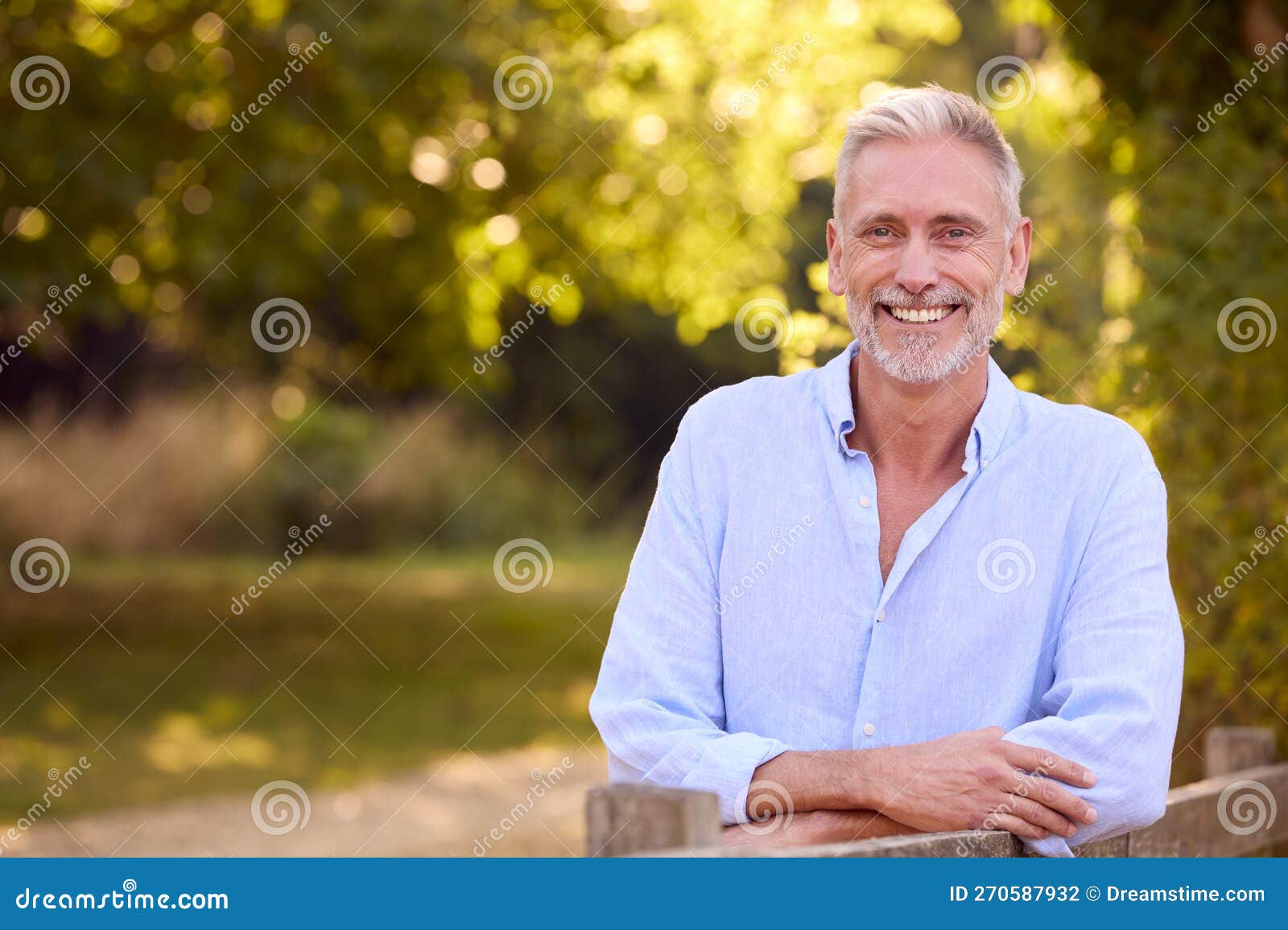 Portrait Of Casually Dressed Mature Man Leaning On Fence On Walk In