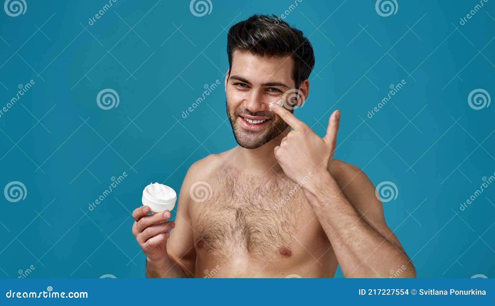 Portrait Of Cheerful Naked Brunette Man Applying Effective Cream On His