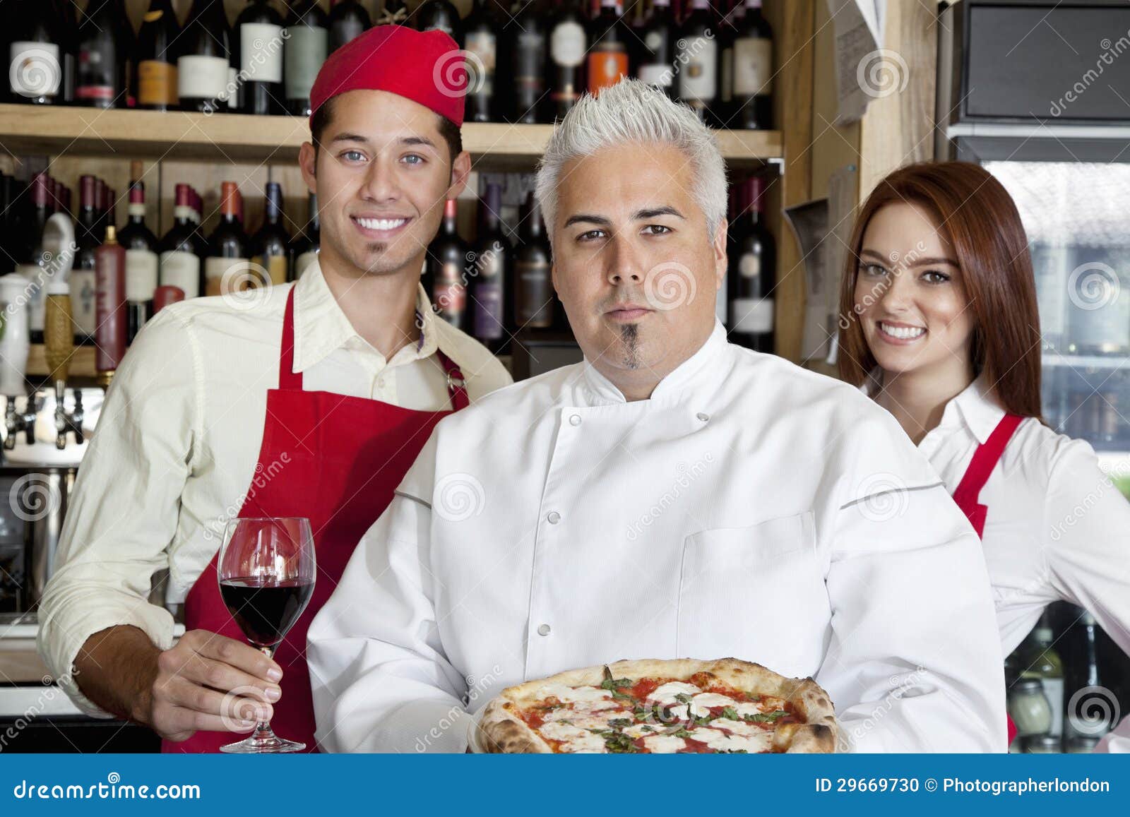 Portrait of a Confident Chef Holding Pizza with Wait Staff in ...