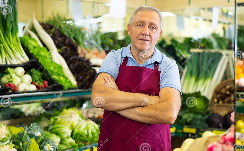 Portrait Of Confident Mature Male Supermarket Worker Wearing Apron