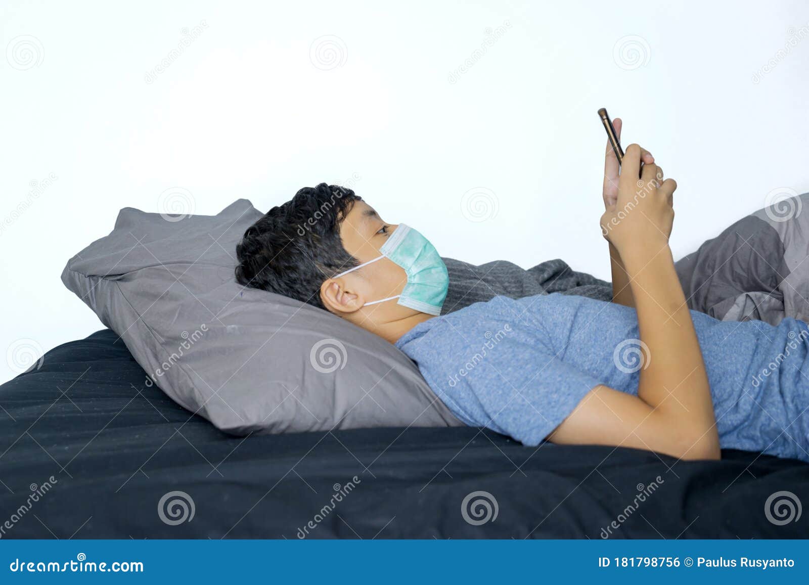 Cute Boy Using Cellphone on the Bed with Mask Stock Photo - Image of ...