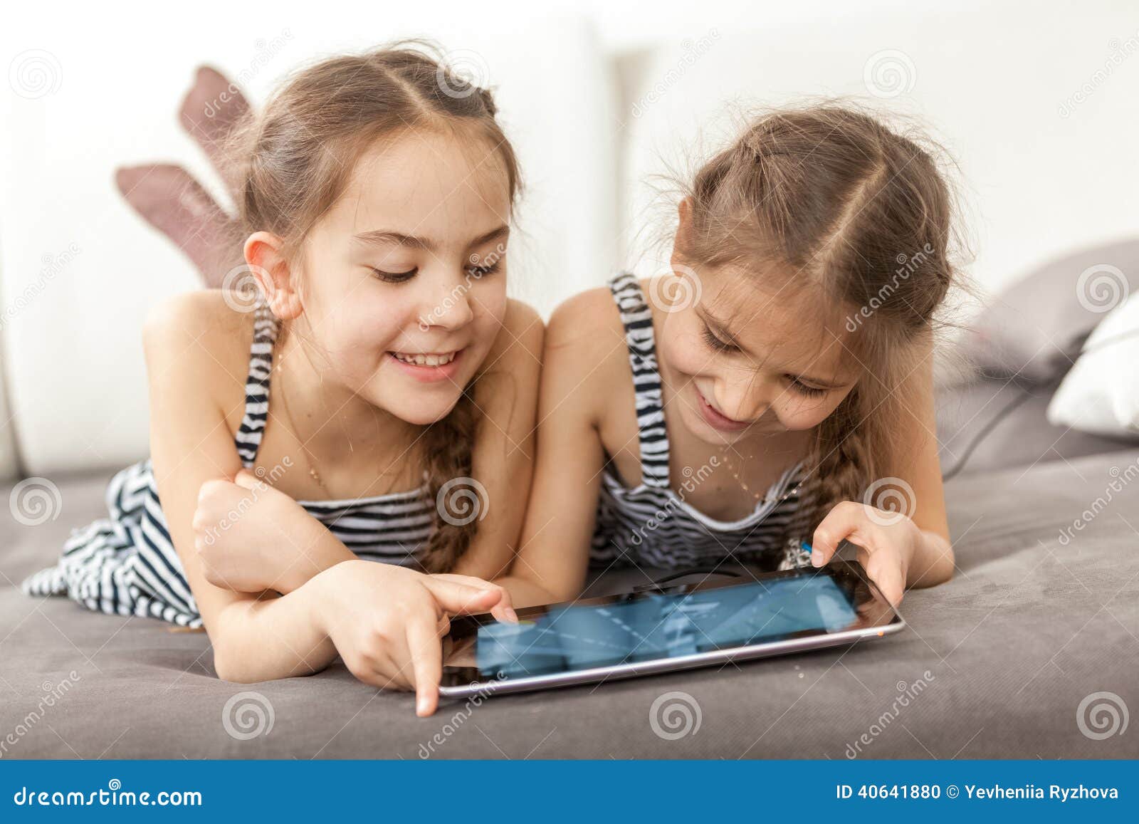 Portrait De Deux Filles De Sourire Se Trouvant Sur Le Divan Et à Laide
