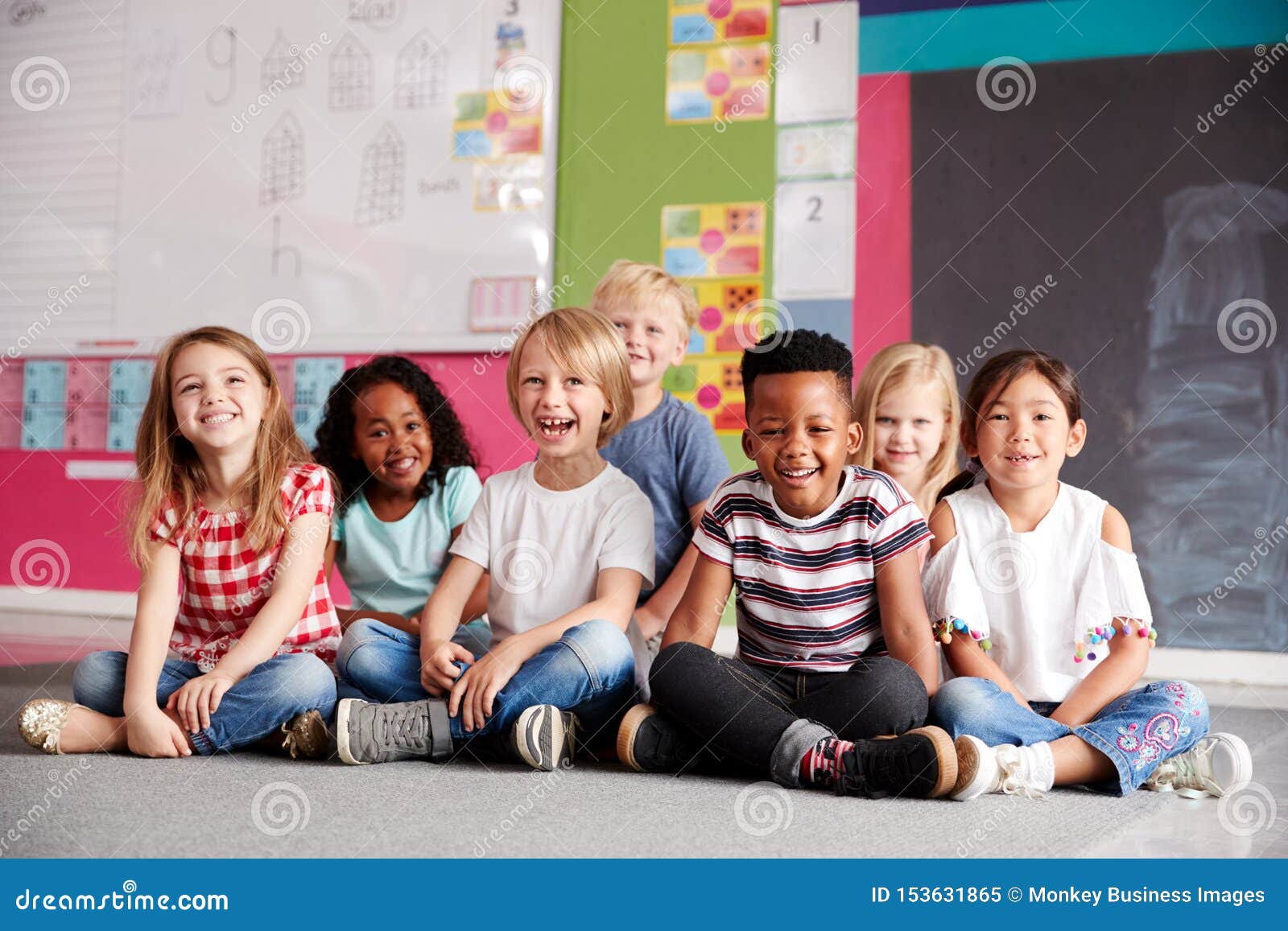 Portrait of Elementary School Pupils Sitting on Floor in Classroom ...