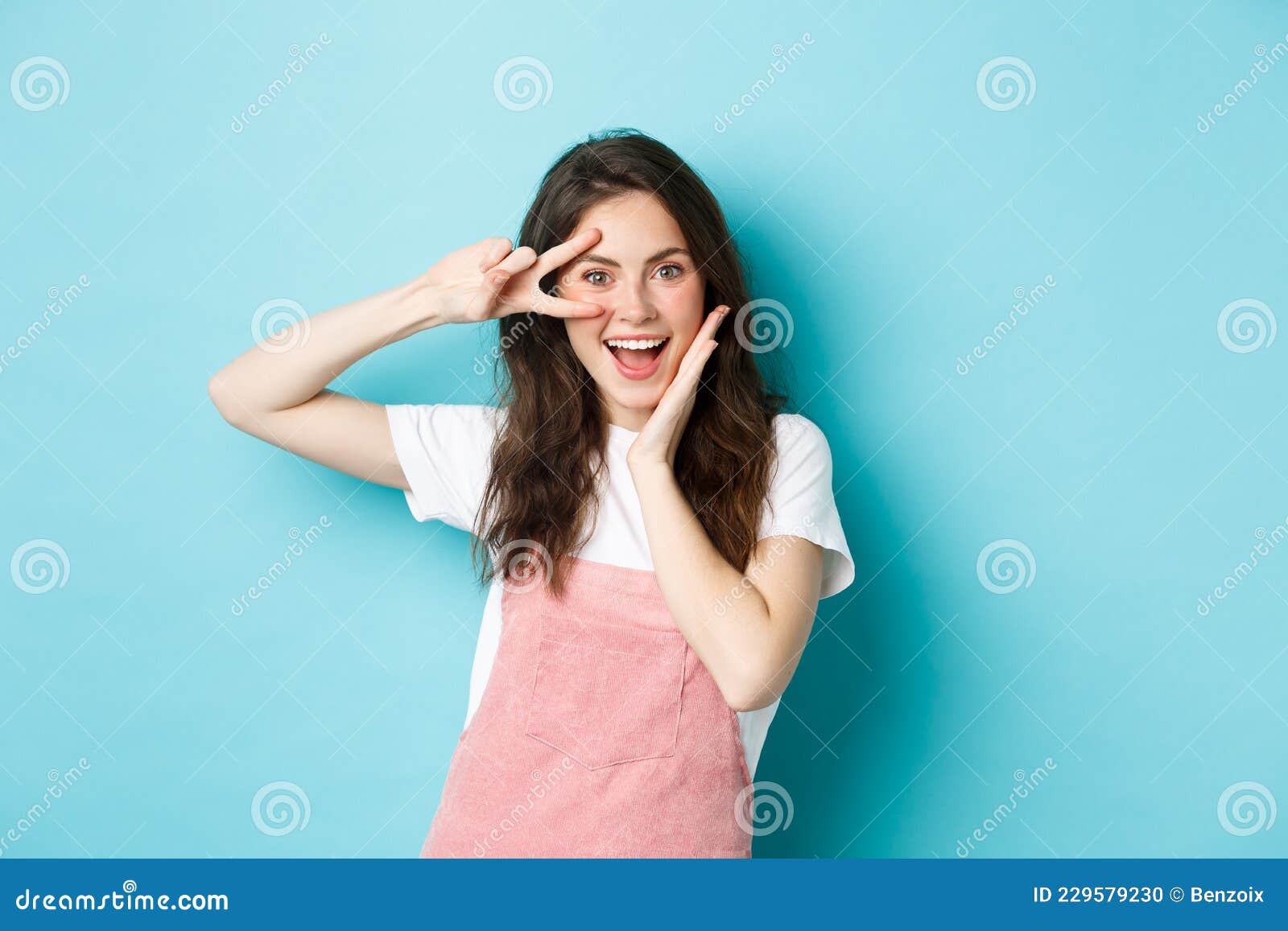 Portrait Of Excited Attractive Woman Showing V Sign Near Eye Making