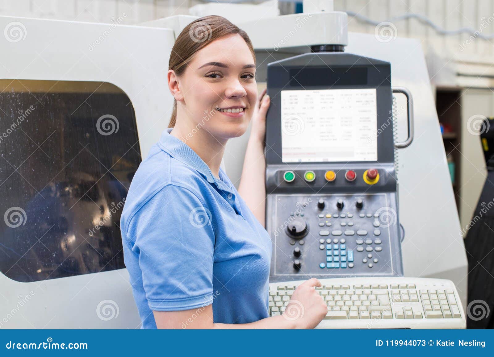 Portrait Of Female Apprentice Engineer Operating Cnc Machine In Stock