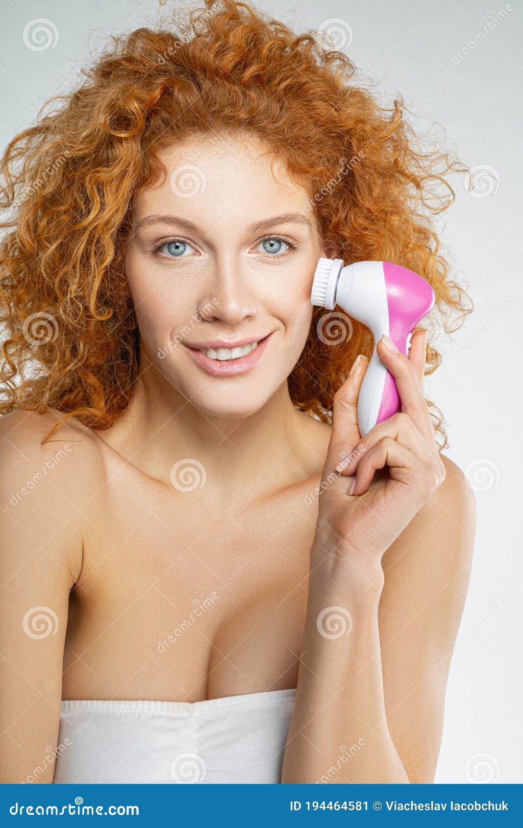 Female Massaging Her Cheek With A Facial Cleansing Brush Stock Image