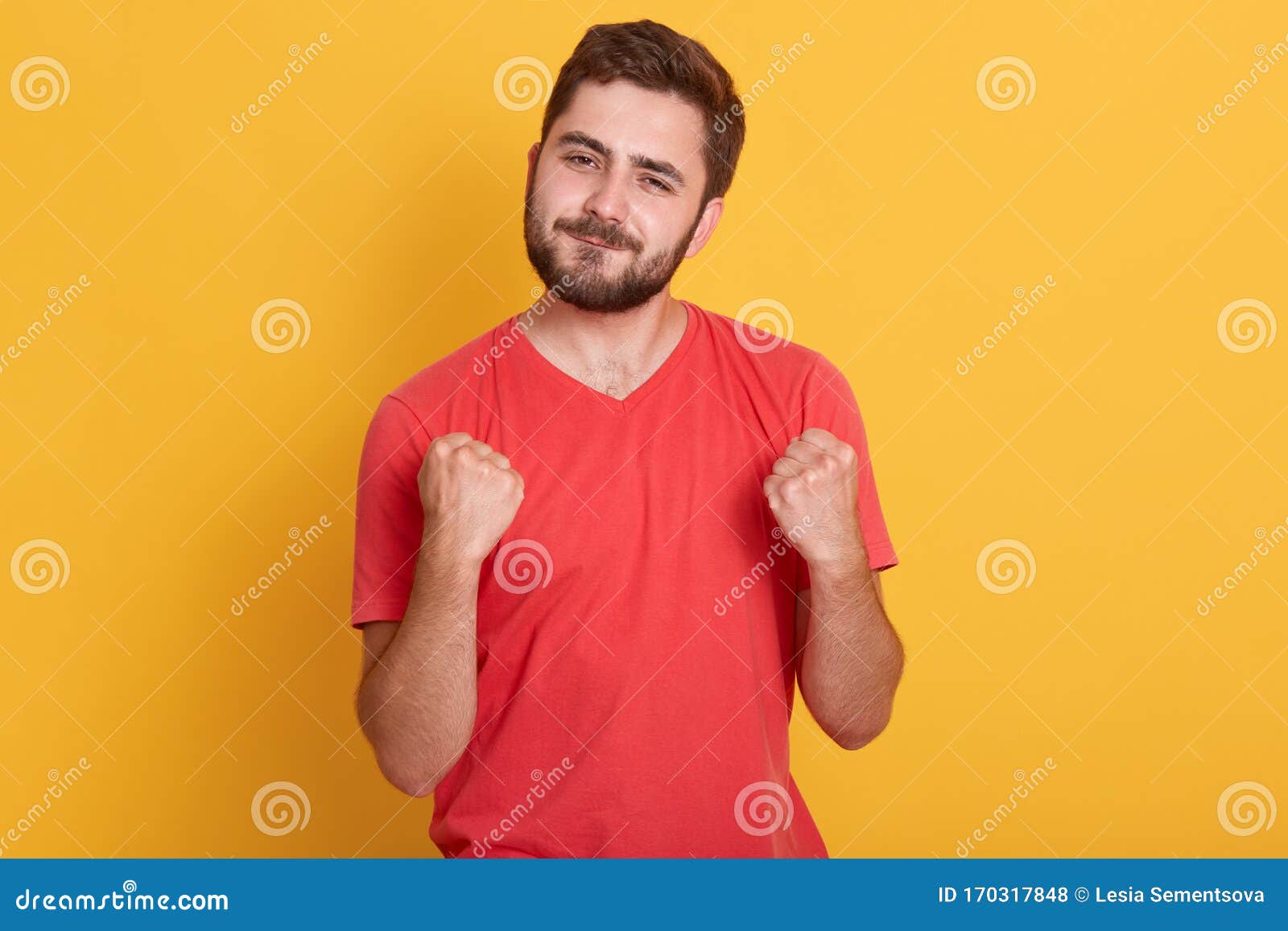 Portrait Of Grinning Excited Bearded Man Clenching Fists Near Chest And