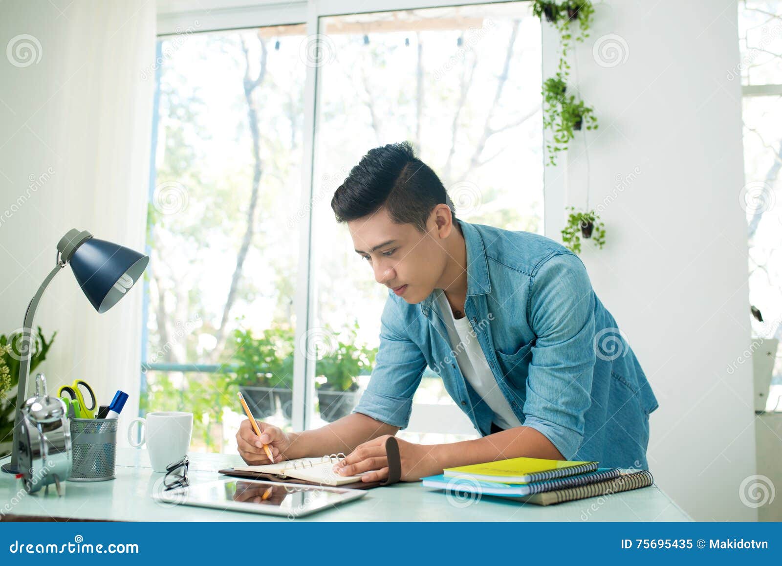 Young Guy Writing In A Note Book Sitting Outside On Wooden Bench ...