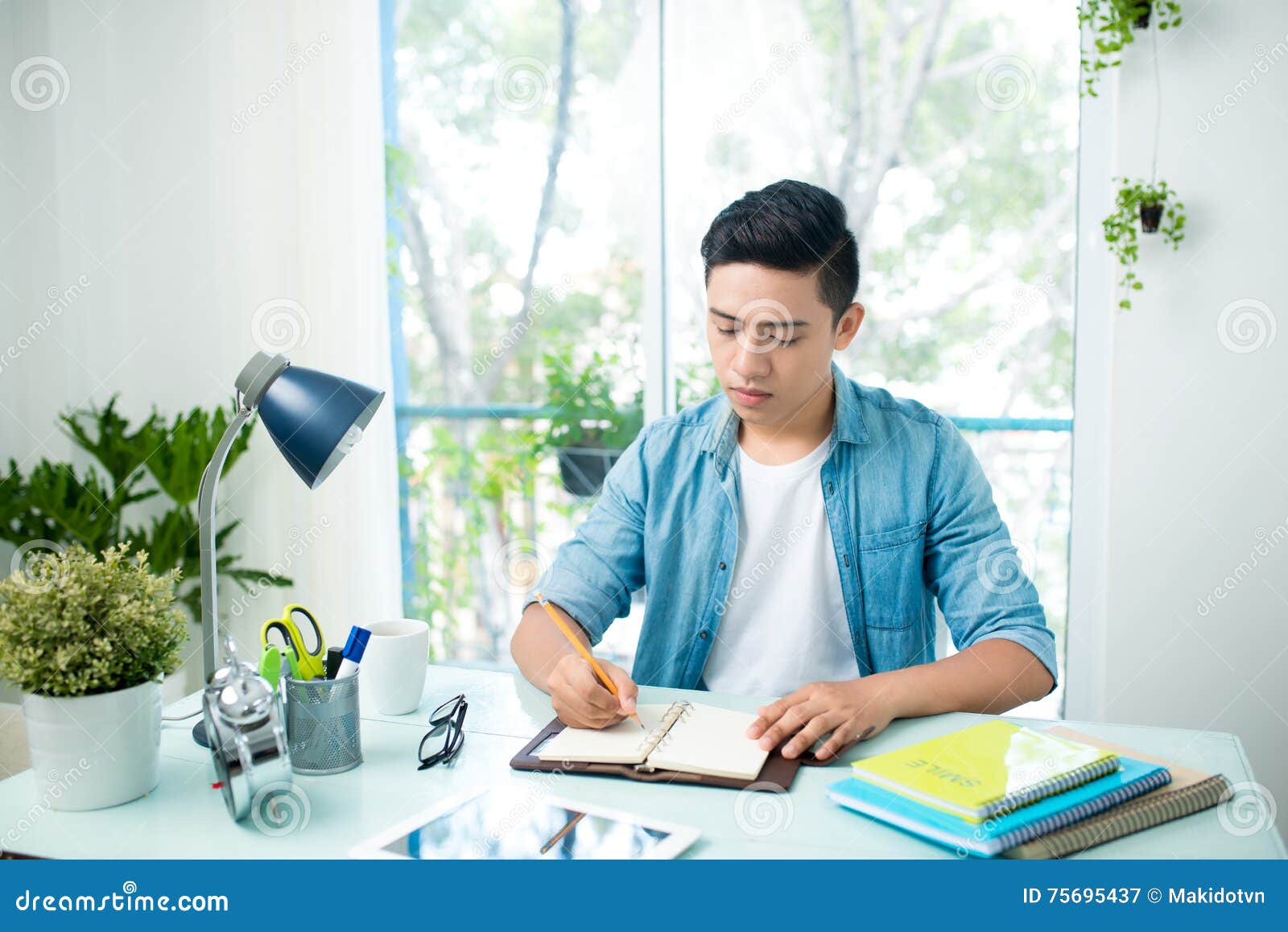 Young Guy Writing In A Note Book Sitting Outside On Wooden Bench ...