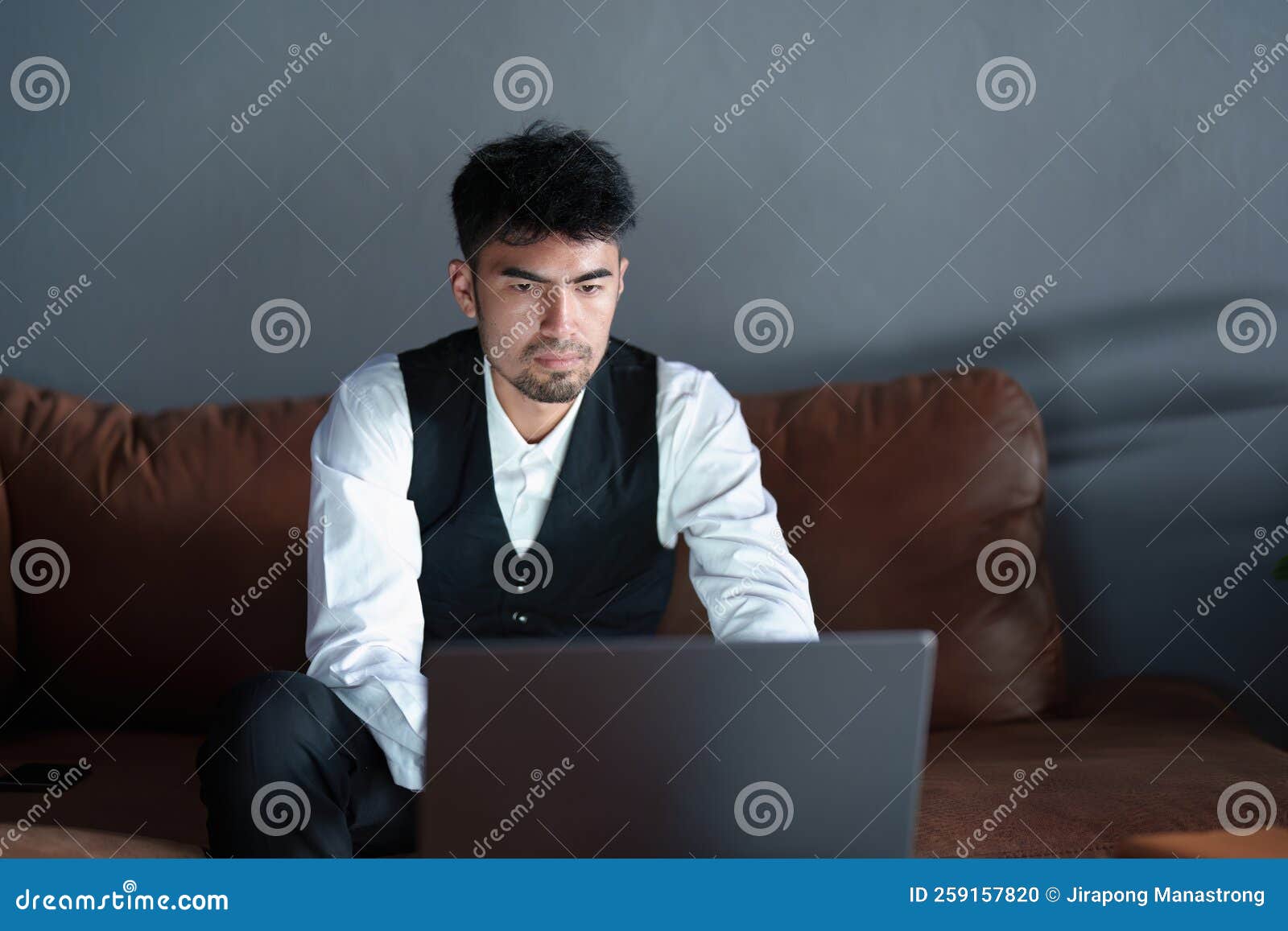 Portrait of a Handsome, Discreet Asian Man Sitting on the Sofa Using a ...