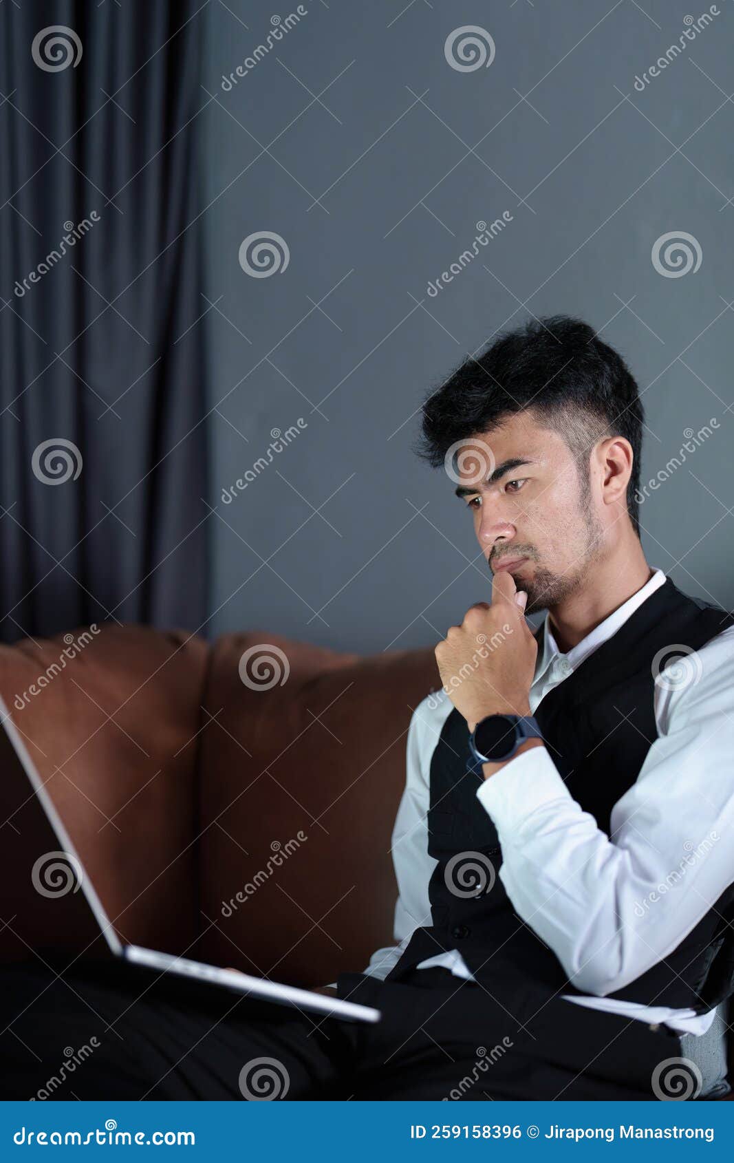 Portrait of a Handsome, Discreet Asian Man Sitting on the Sofa Using a ...