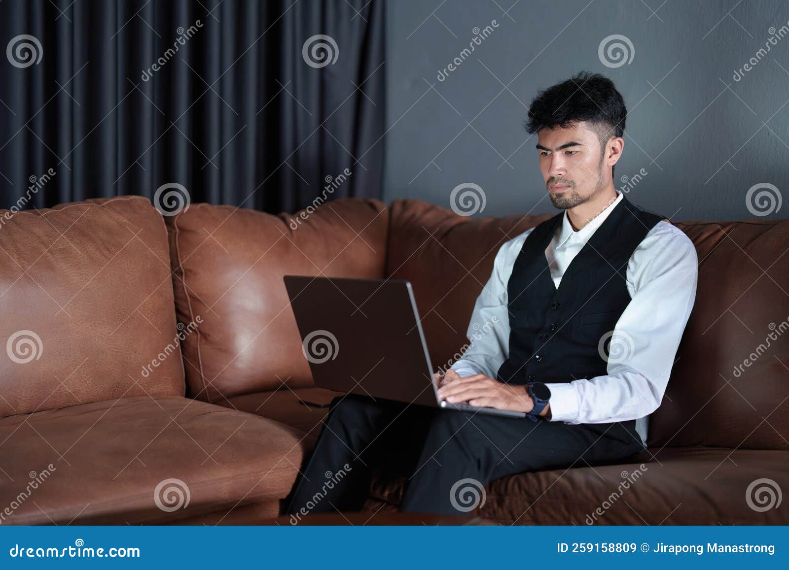 Portrait of a Handsome, Discreet Asian Man Sitting on the Sofa Using a ...