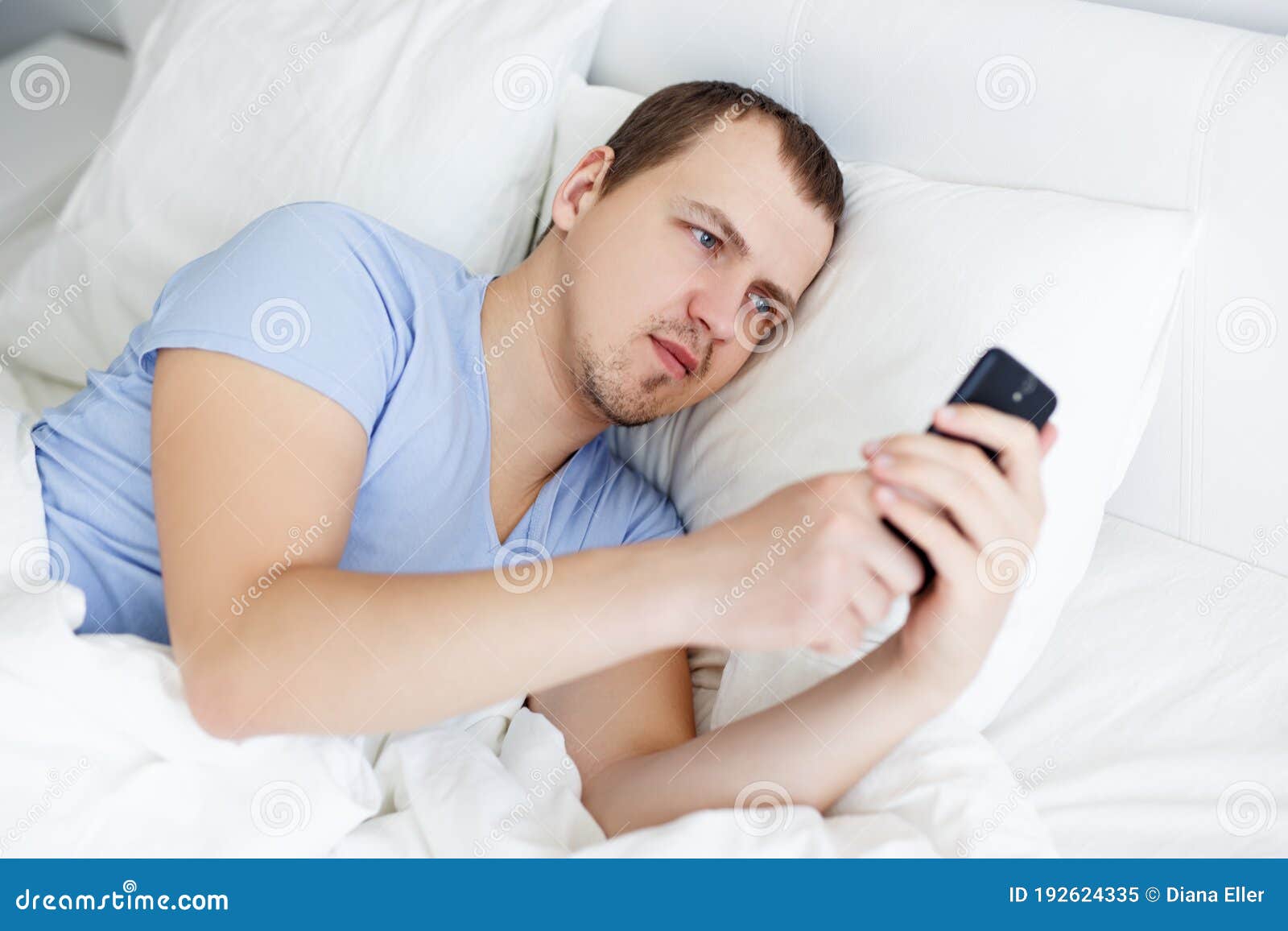 Portrait of Handsome Young Man Using Smartphone Lying in Bed Stock ...