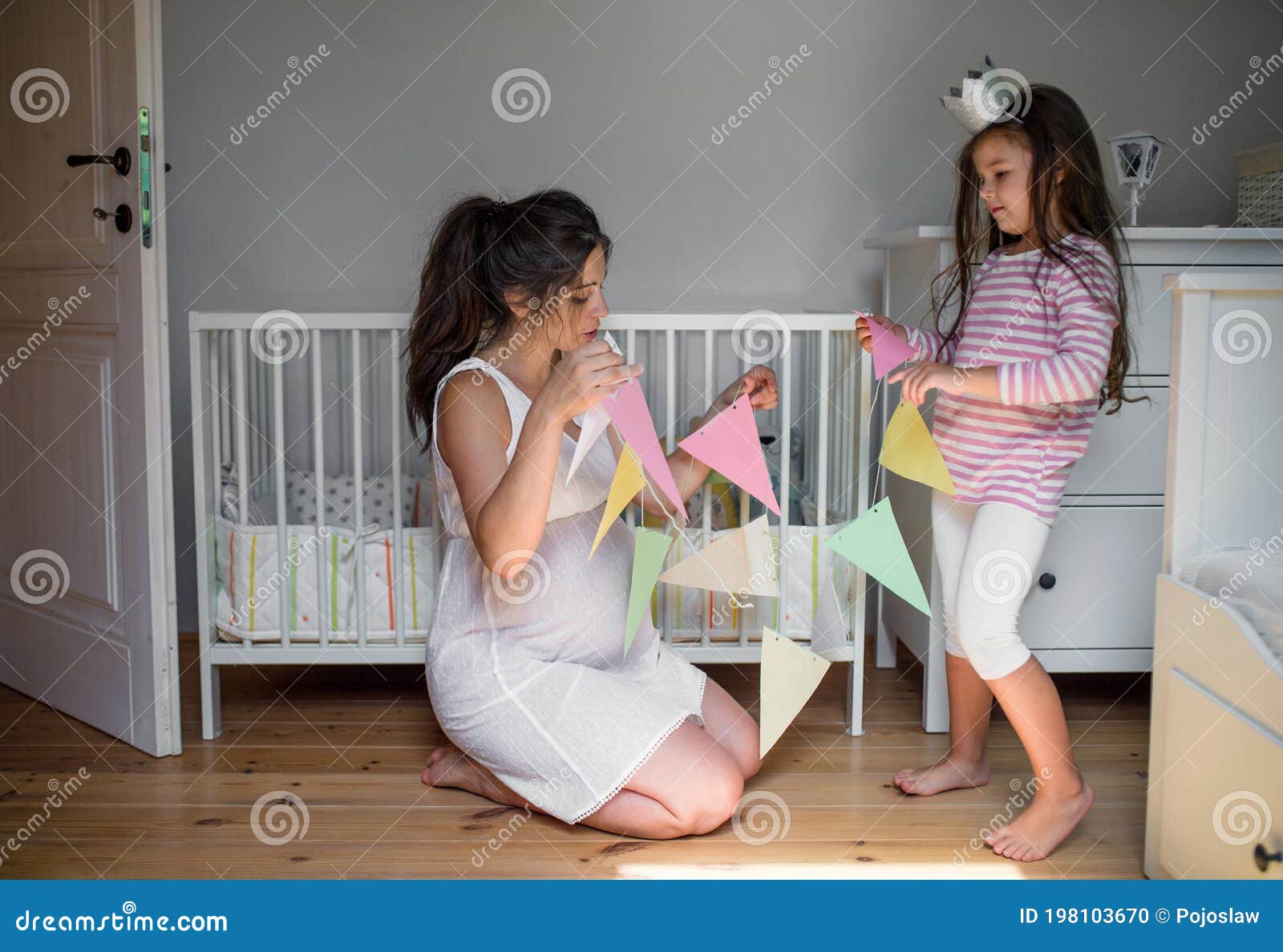 Portrait Of Pregnant Woman With Small Daughter Indoors At Home