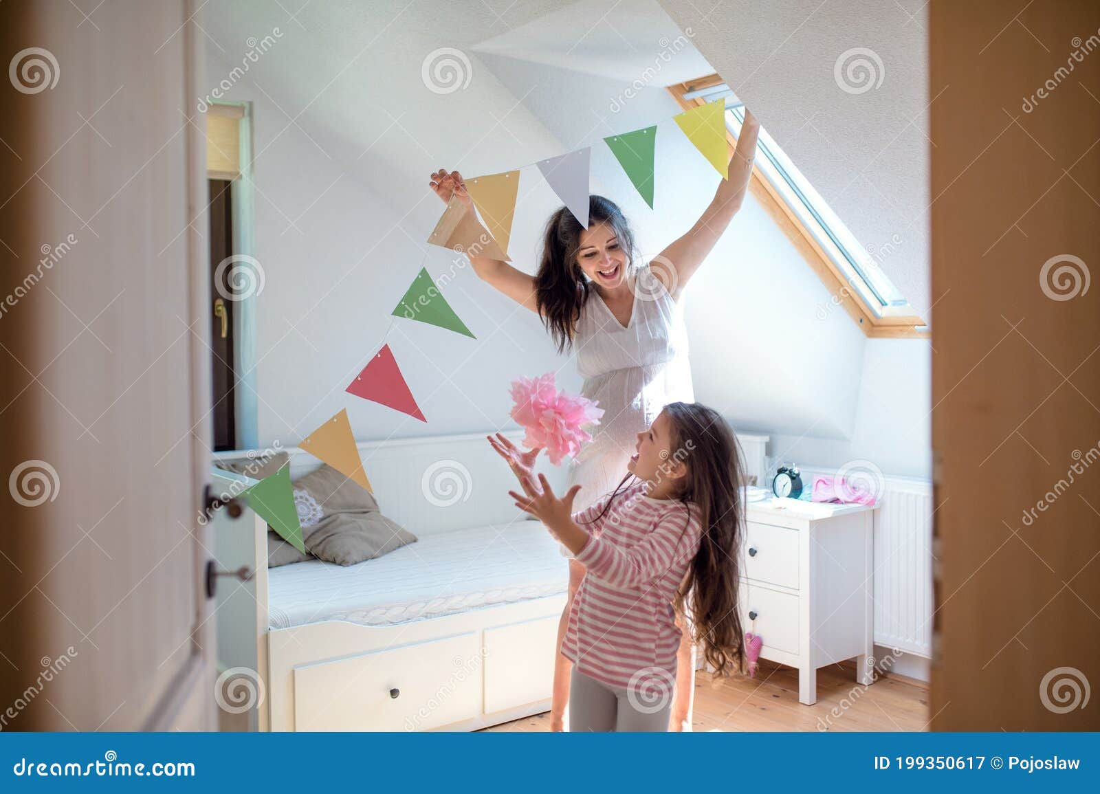 Portrait Of Pregnant Woman With Small Daughter Indoors At Home