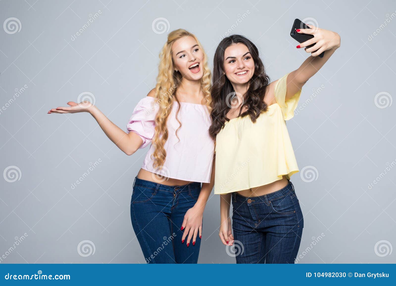 Portrait Of A Happy Two Smiling Girls Making Selfie Photo On Smartphone