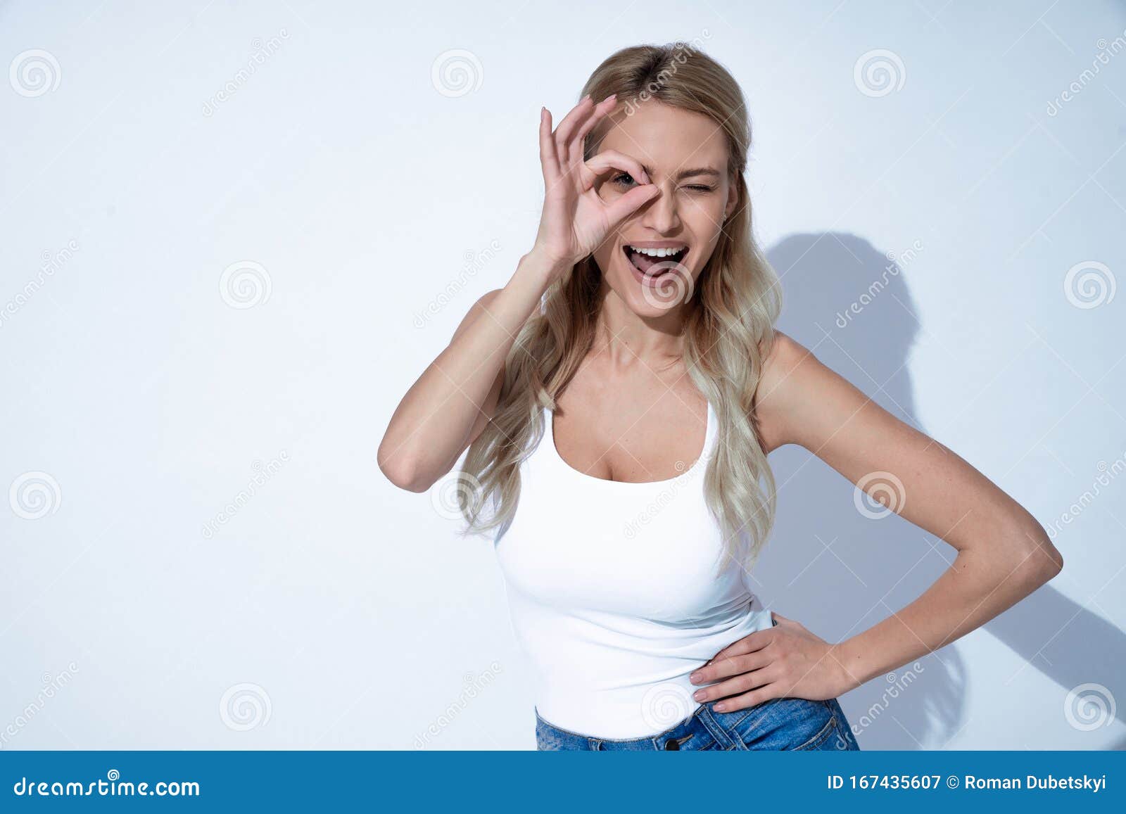 Portrait Of A Happy Young Blonde Girl Showing Ok Gesture Over Her Eyes