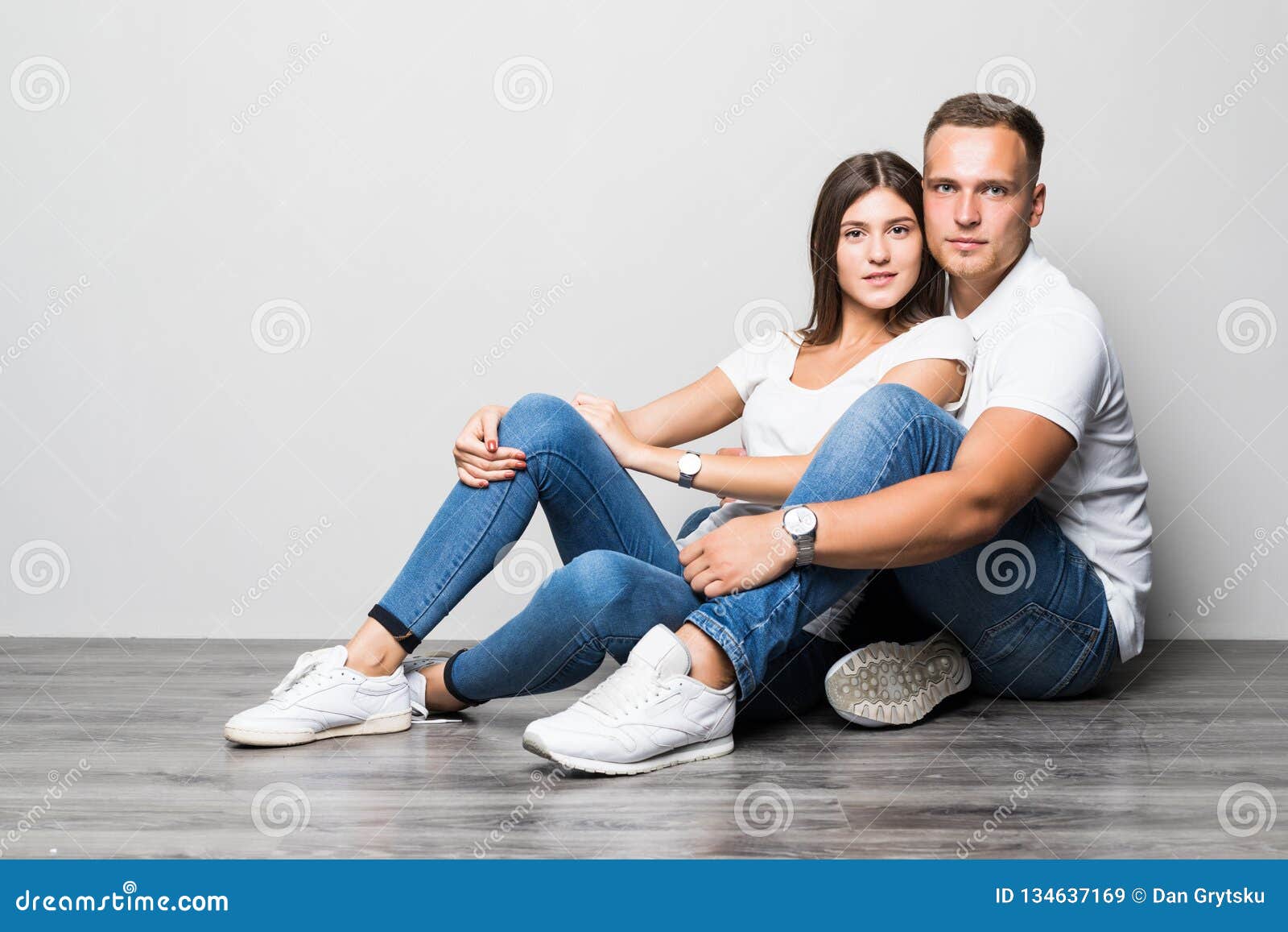 Portrait of a Happy Young Couple Hugging Sitting Together Over Beige ... Portrait of a Happy Young Couple Hugging Sitting Together Over Beige ...